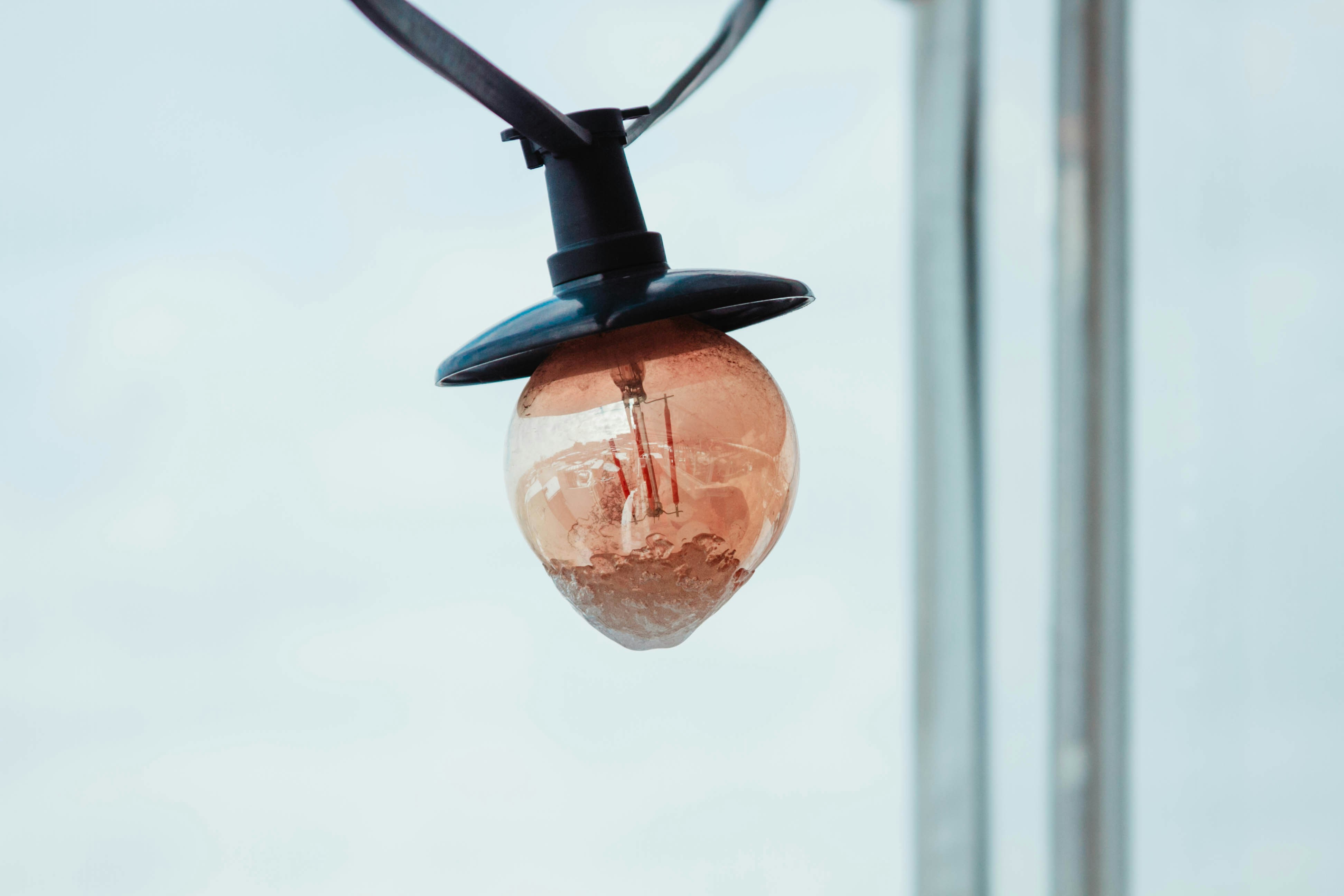 Hanging Globe: A Warm Light Bulb Against a Pale Sky