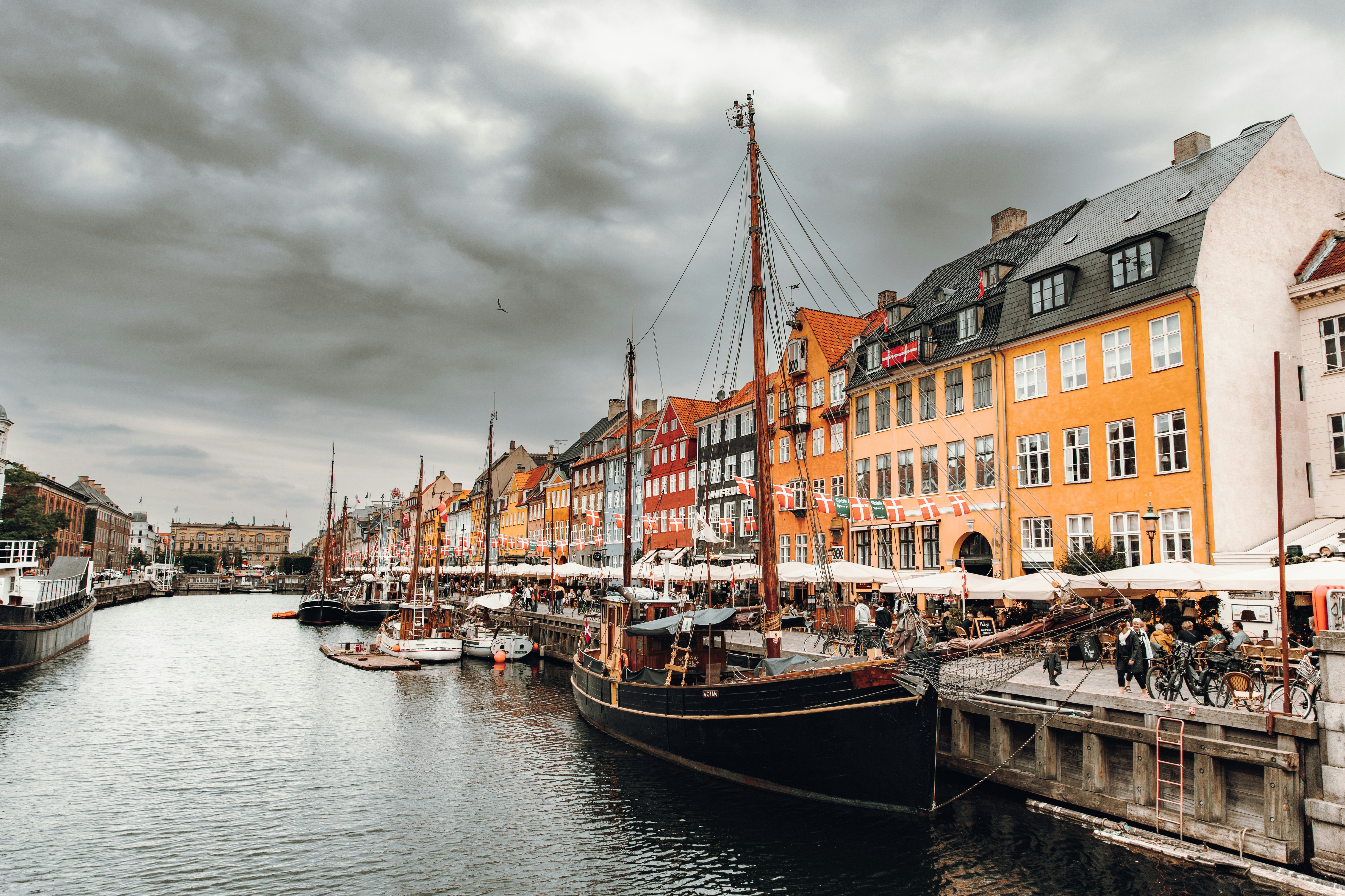 Copenhagen on a moody day! 🇩🇰 | a boat is docked in the water next to a row of buildings