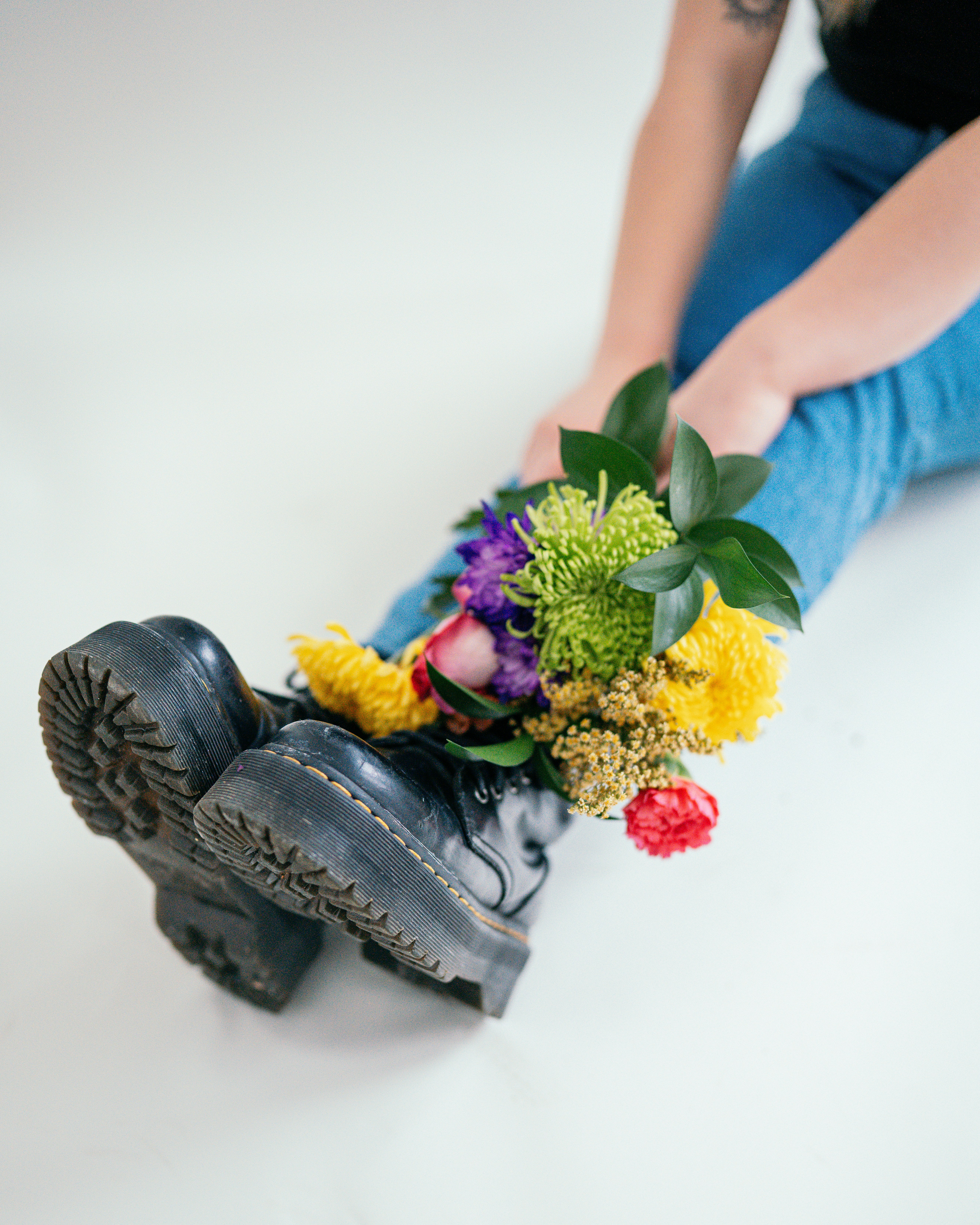 A pair of black boots adorned with vibrant flowers, showcasing a blend of nature and fashion. The arrangement highlights the contrast between rugged footwear and delicate blooms.