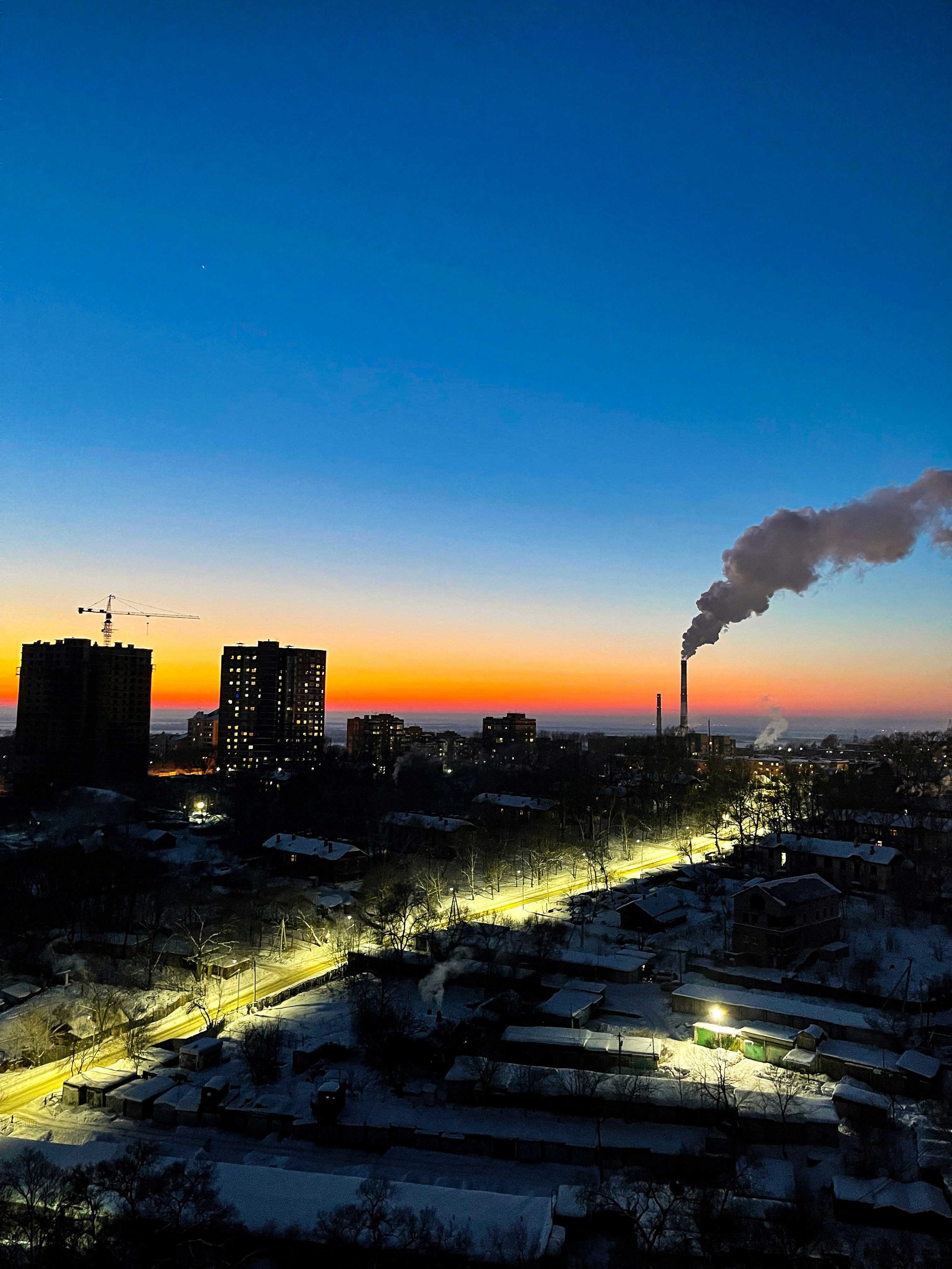 Industrial glow at dusk: city street chased by a smokestack