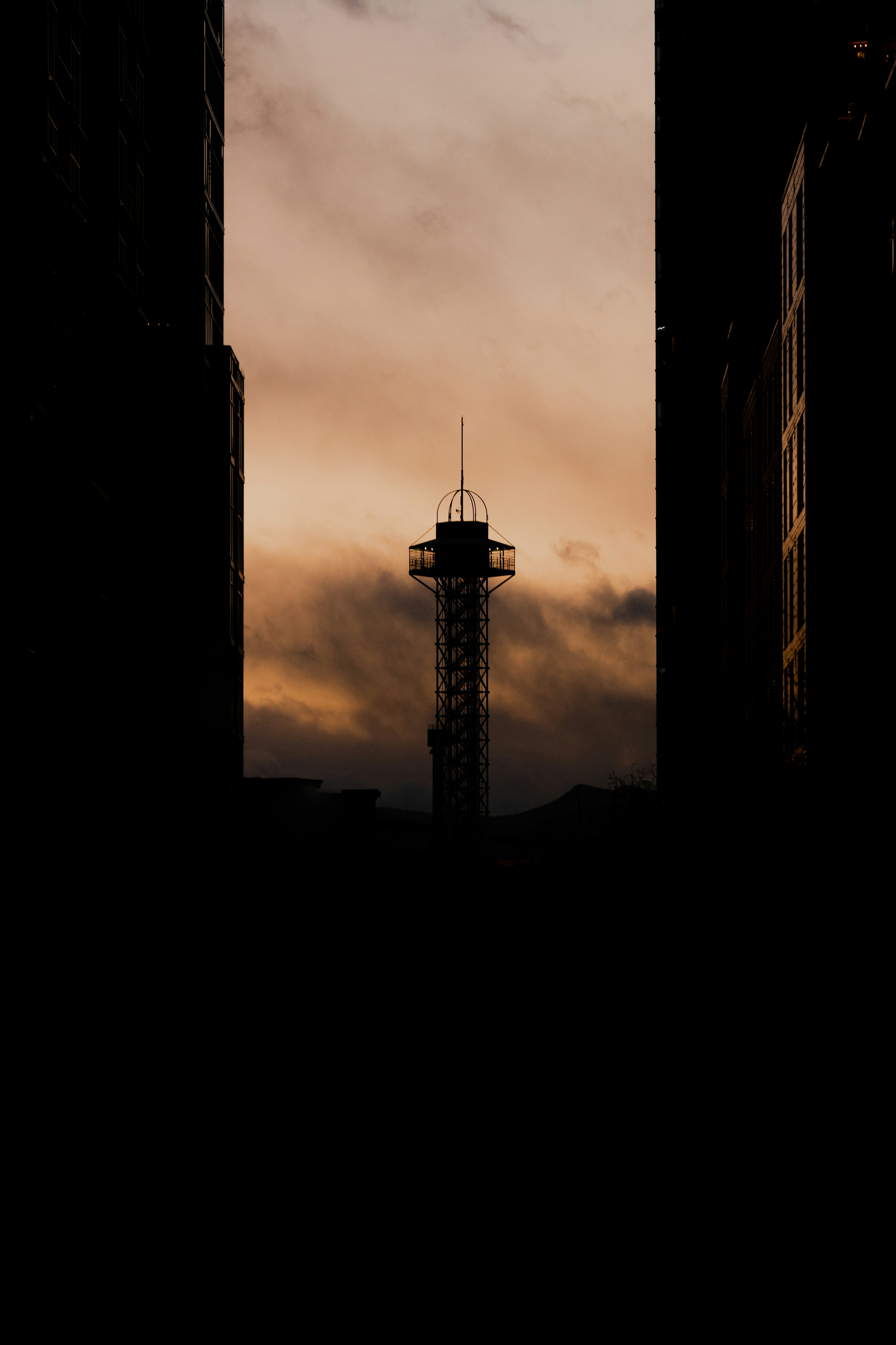Silhouette of a Skyward Watchtower Framed by Urban Shadows at Dusk