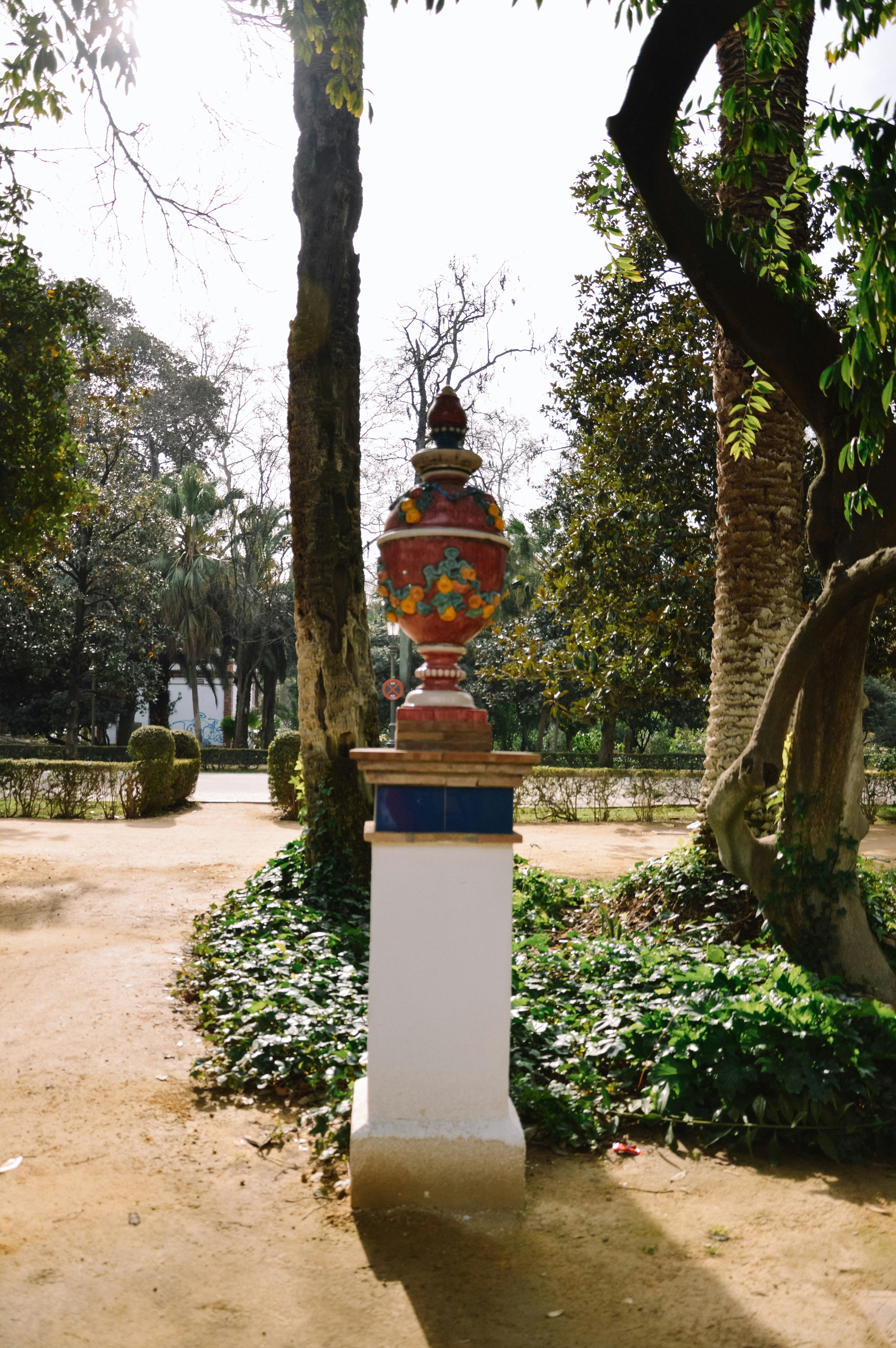 Sunlit Urn Between Trees: A Quiet Park Monument