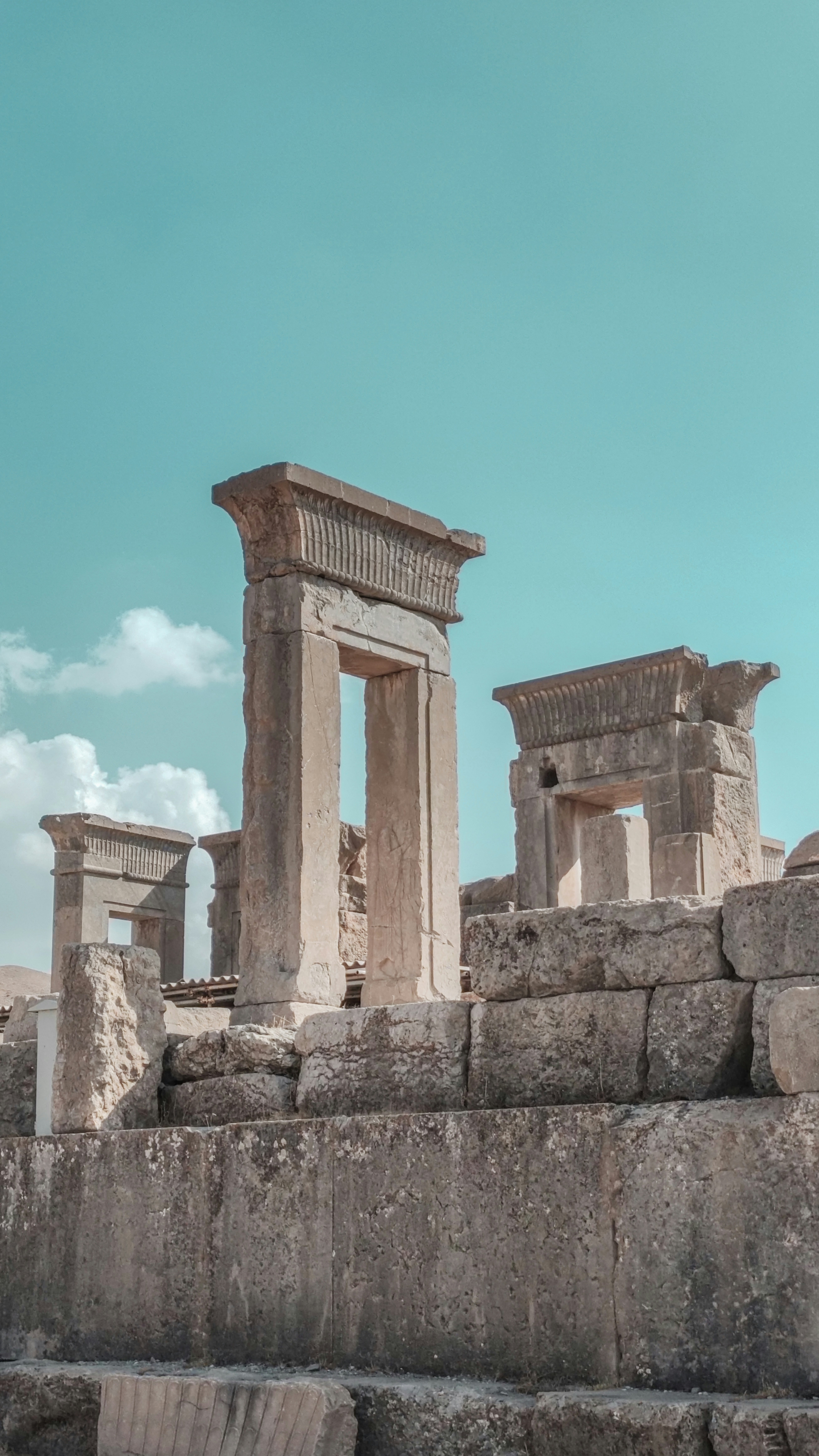 Weathered stone columns rise against a serene blue sky, showcasing the remnants of a bygone civilization.