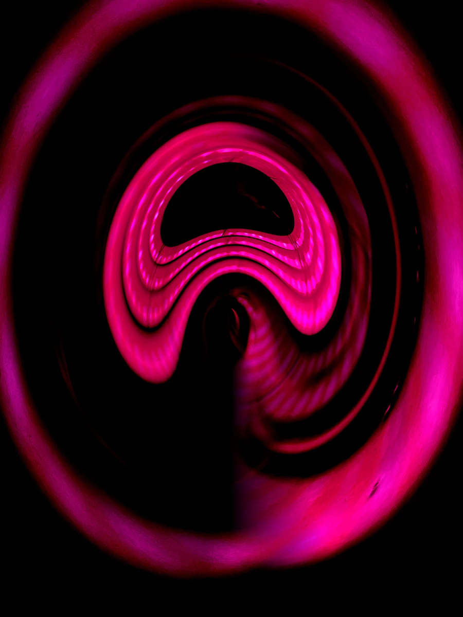 Abstract neon magenta spiral forms glowing rings against a black background, with a dark central void and swirling streaks around it.