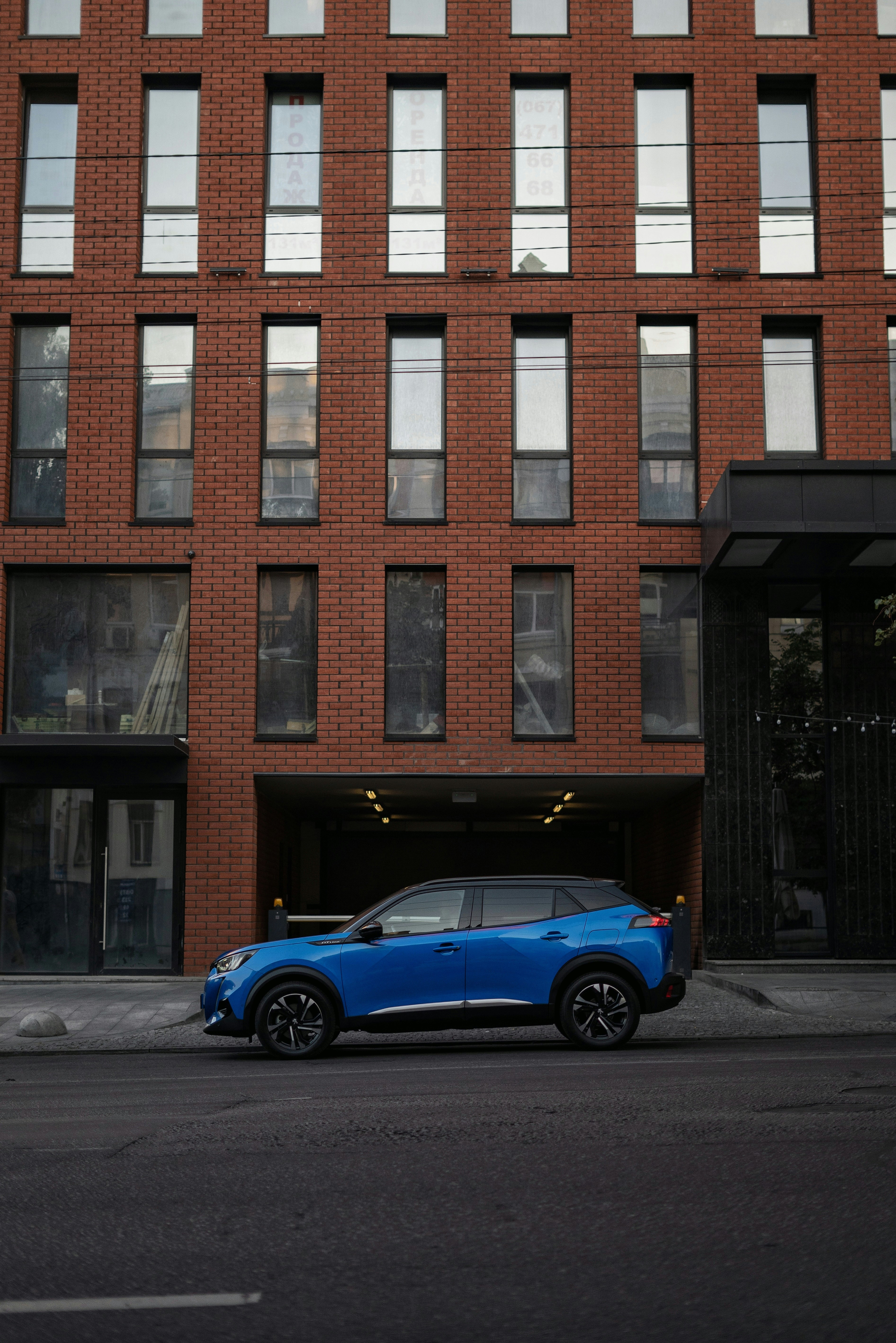 Blue Crossover Amid a Red Brick Office Facade
