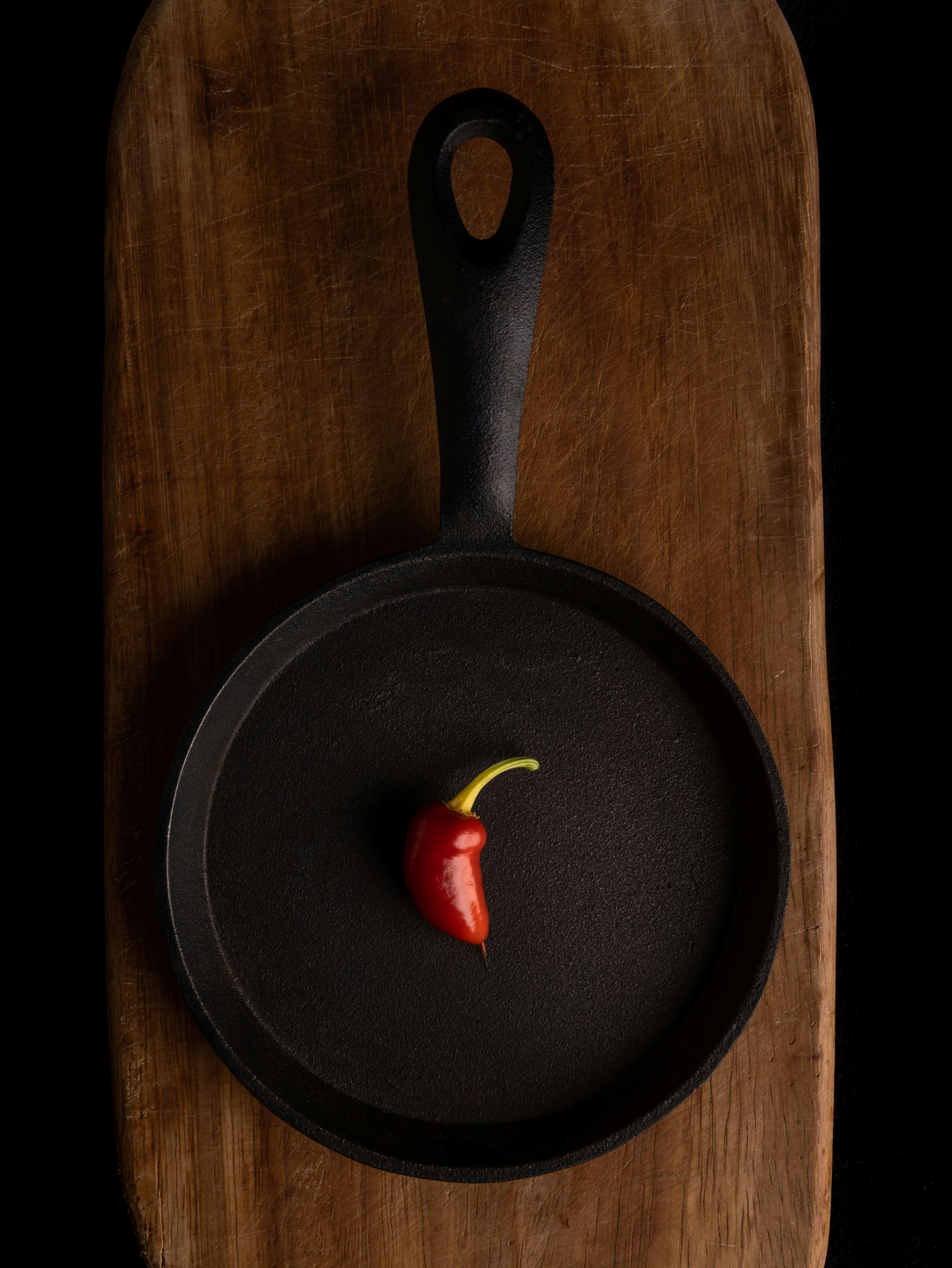 a red pepper sitting on top of a frying pan