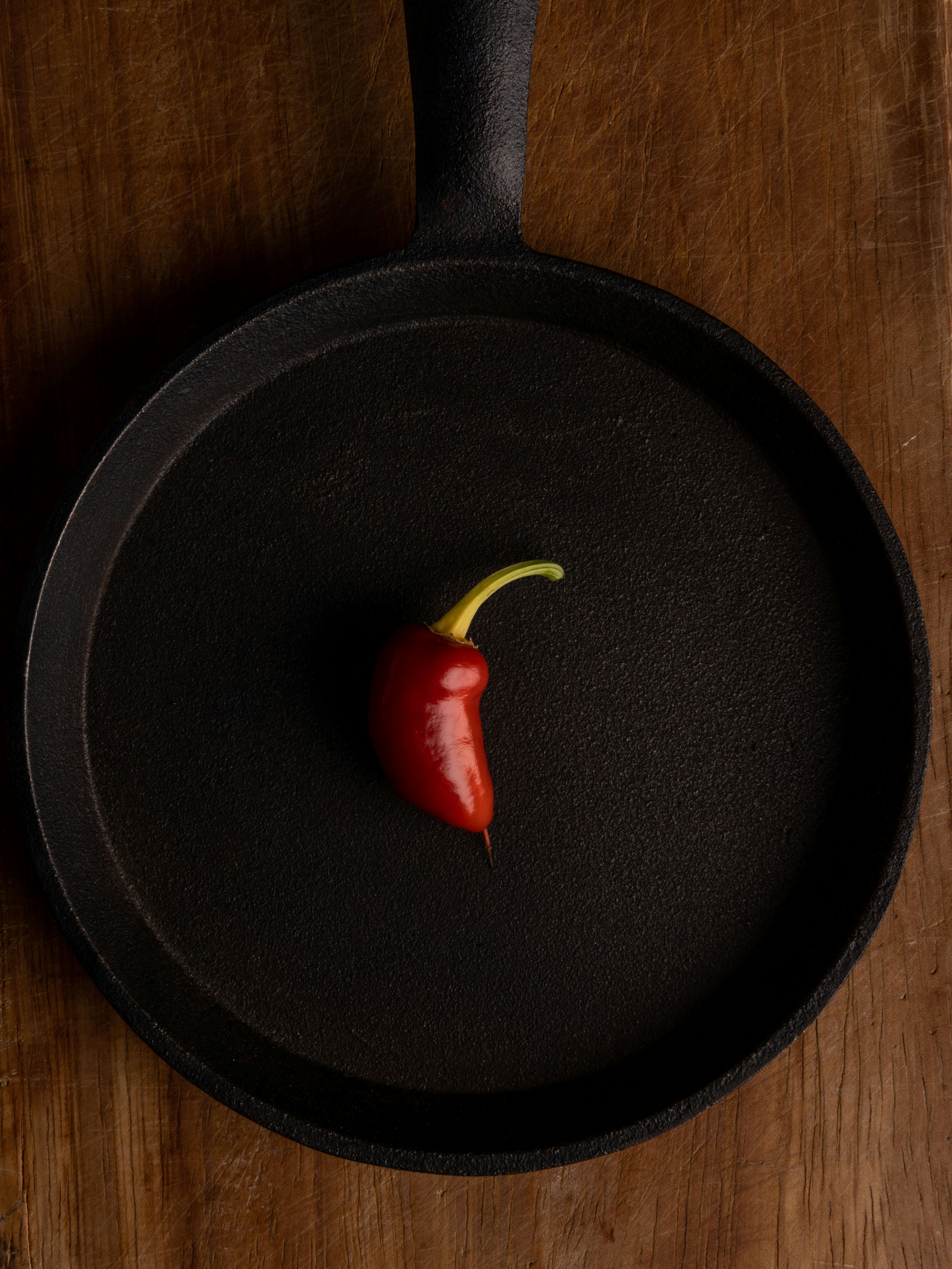 a red pepper sitting on top of a frying pan