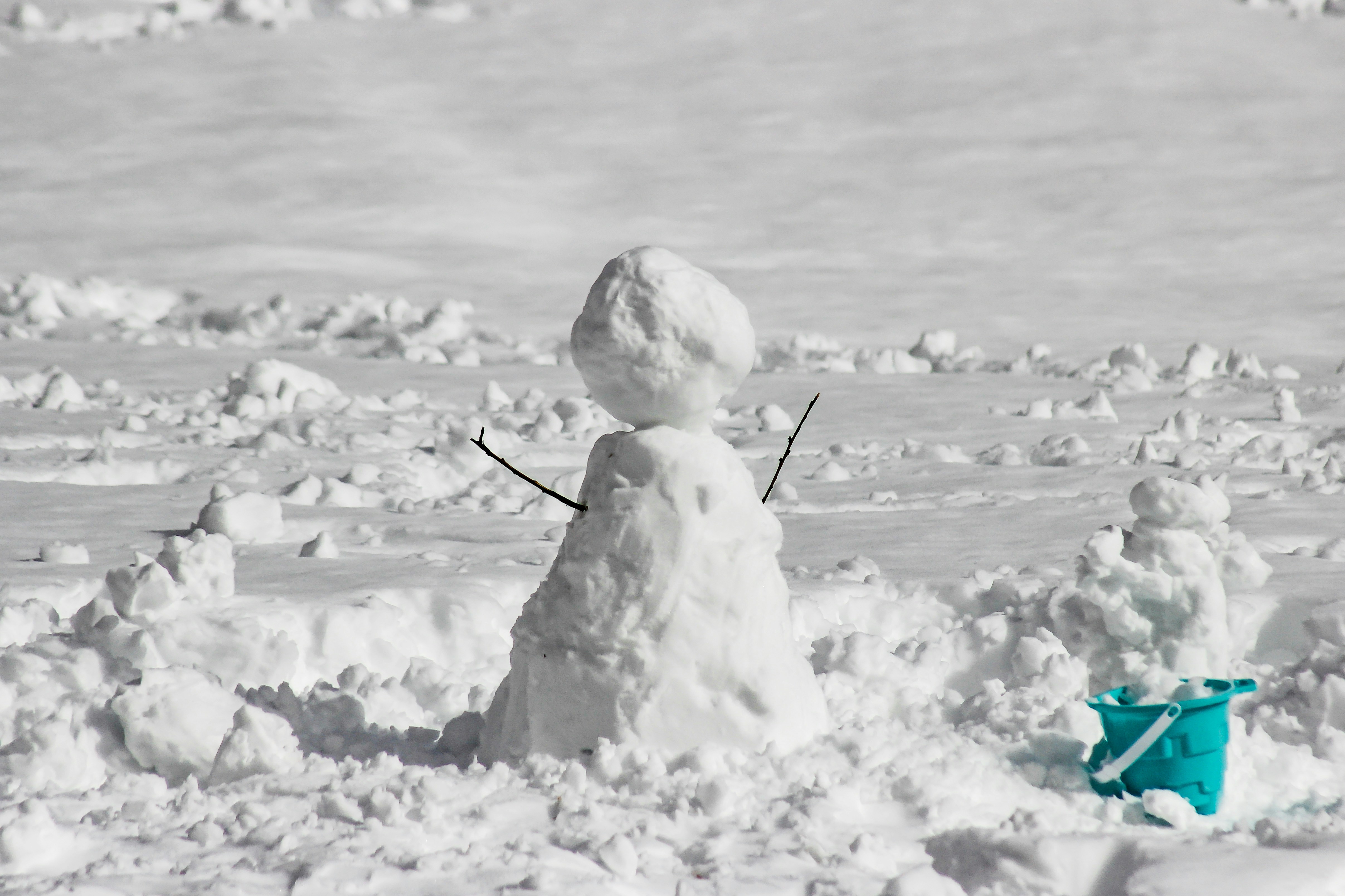 Snow Angel in a Quiet Field: A Small Snowman with a Bright Plastic Bucket