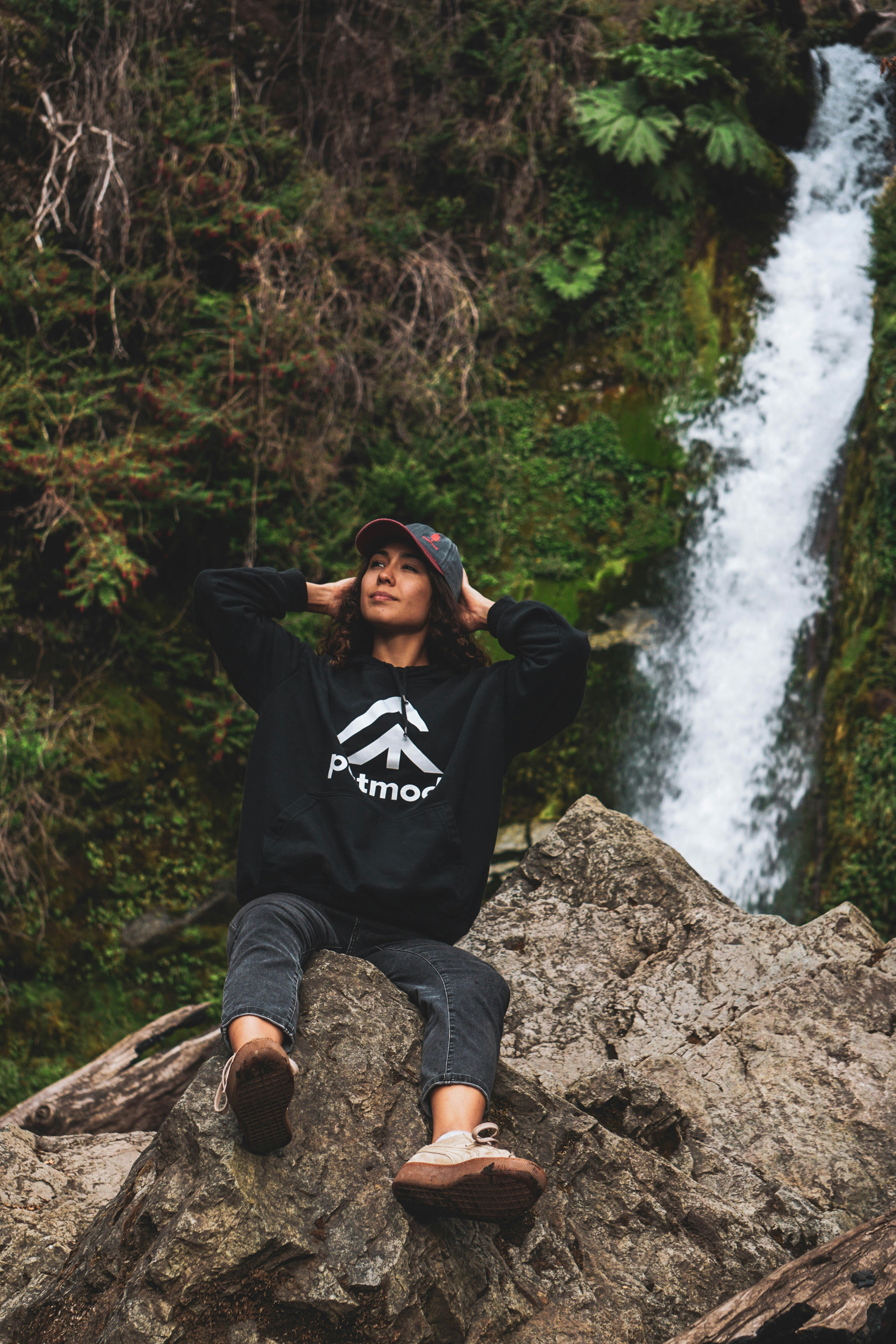 Foto Un hombre sentado en una roca frente a una cascada – Imagen ...