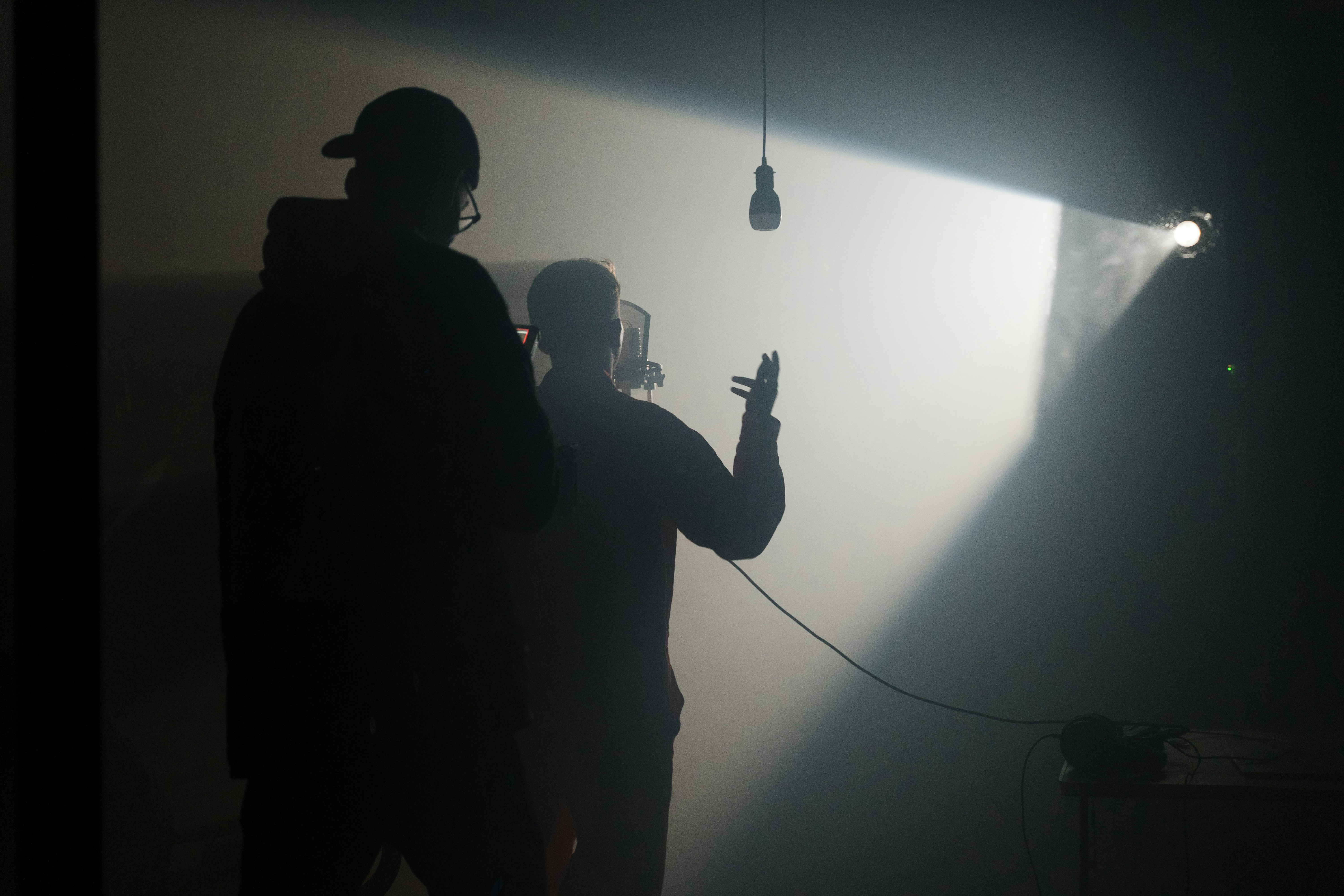 Silhouette of a person holding a microphone with dramatic lighting in a dark room.