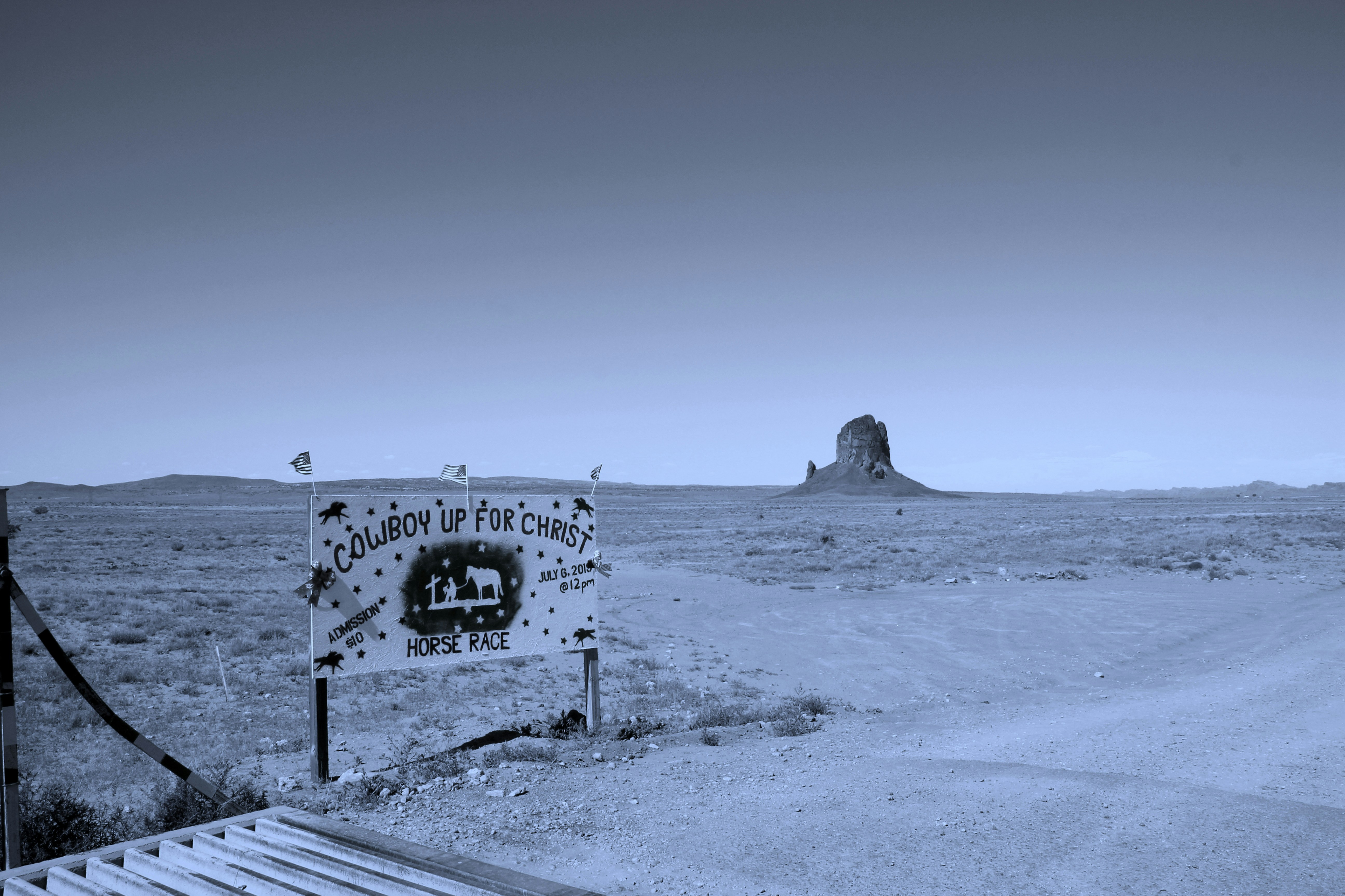 Weathered Signpost and a Lone Butte under a Pale Blue Desert Sky