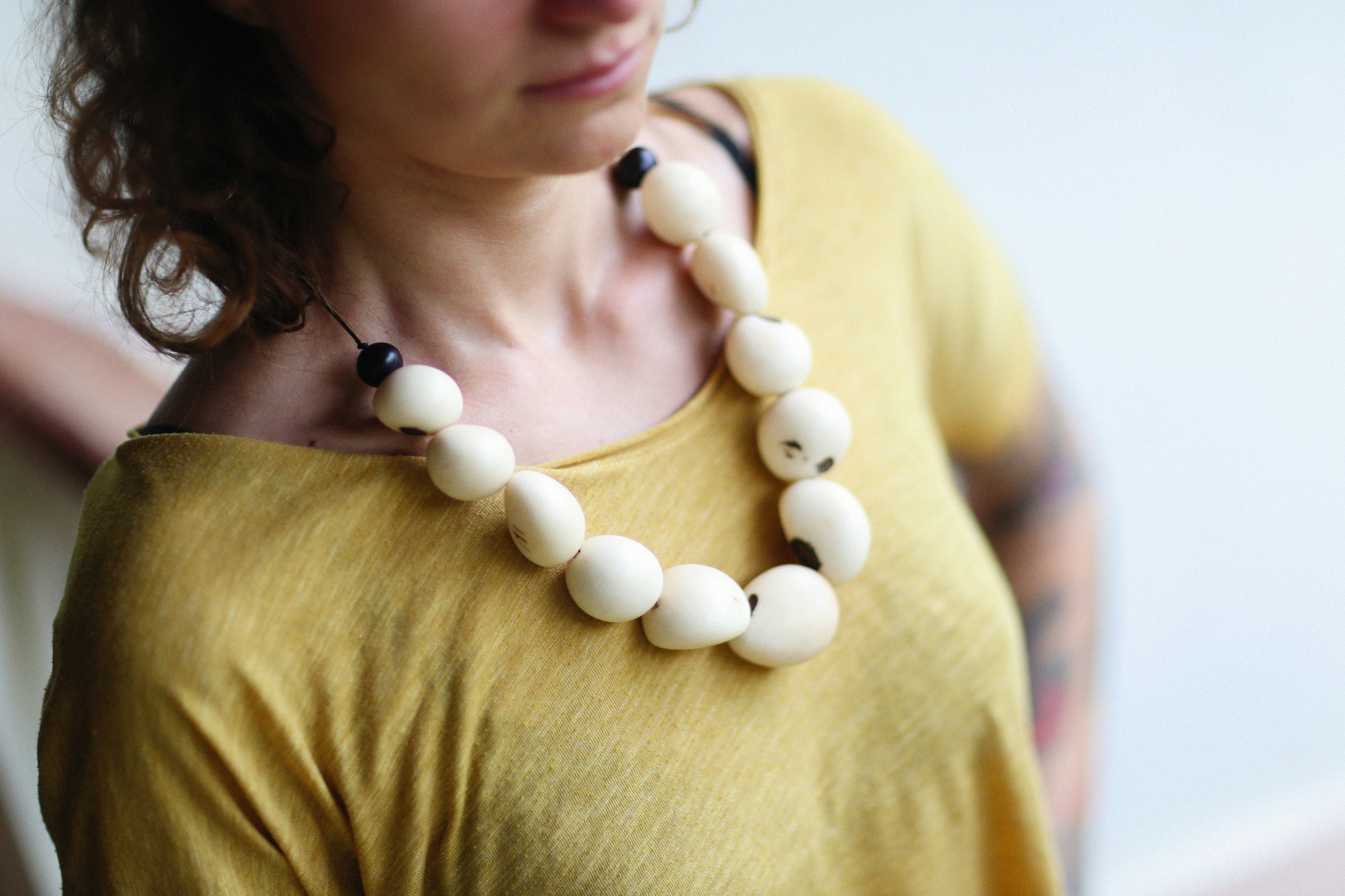 Cream Bead Necklace on a Mustard Top: A Quiet Close-Up