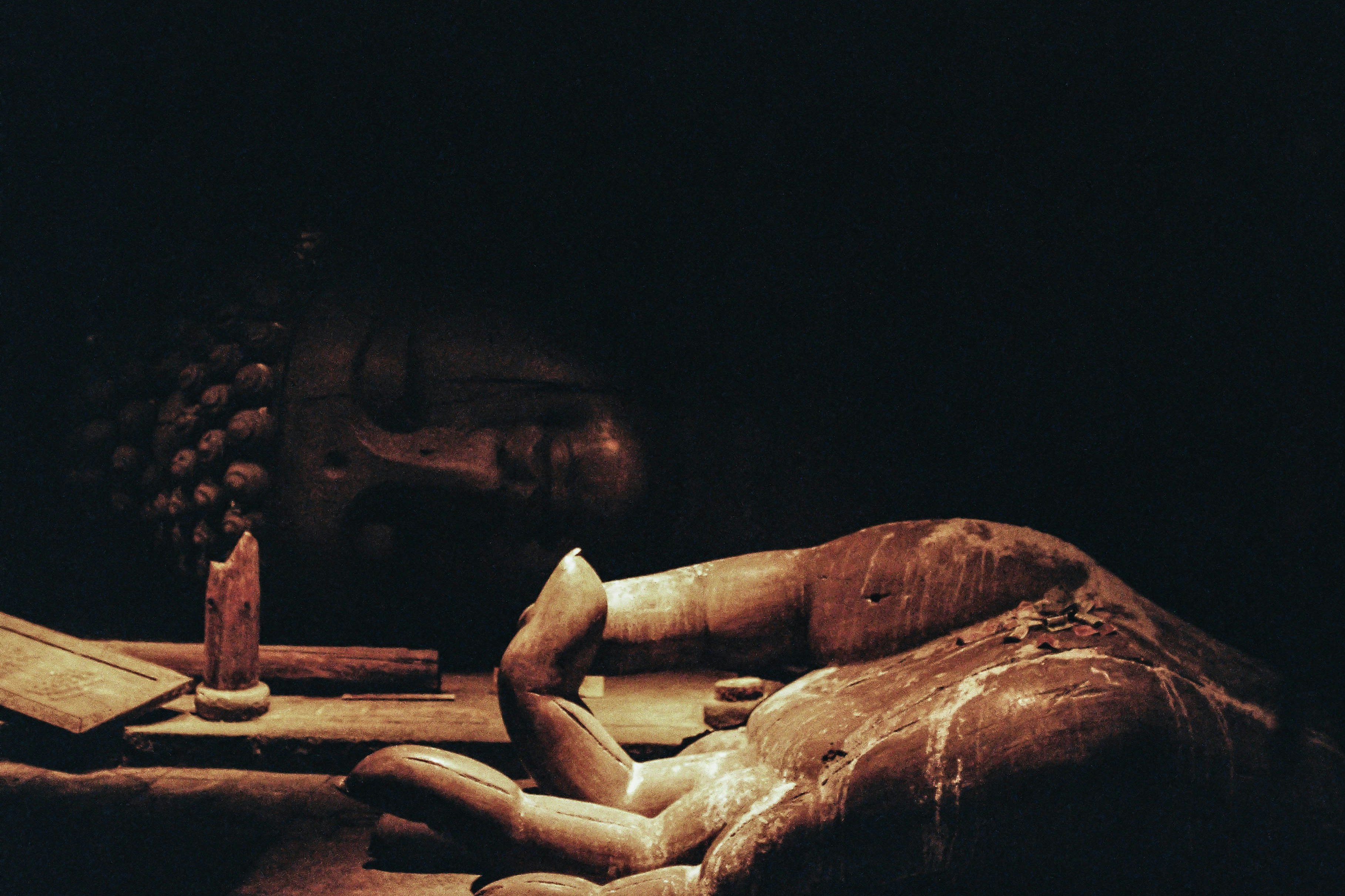 Reclining Buddha sculpture in a dimly lit room, highlighting serene facial features and detailed hand carvings.