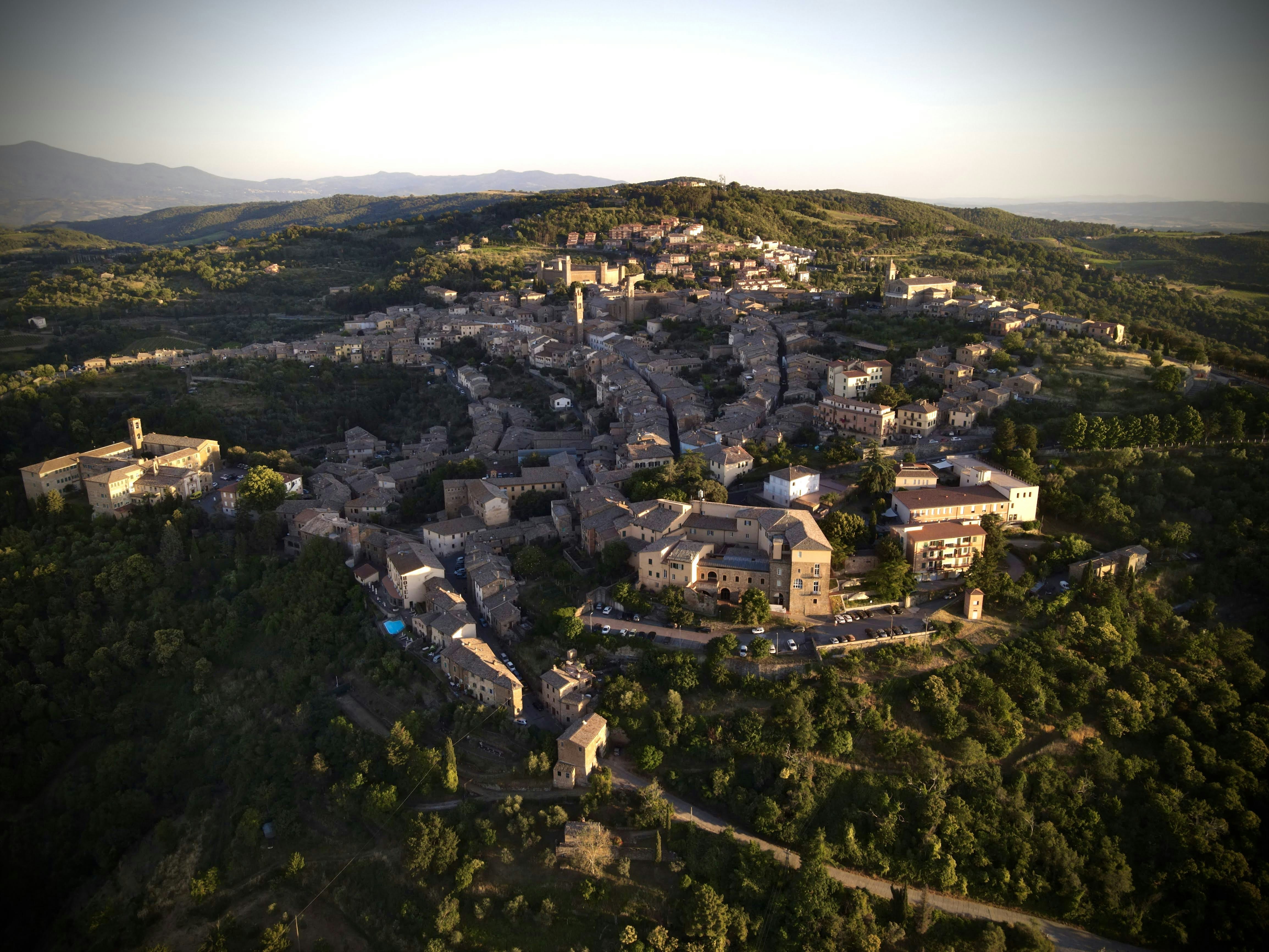 Aerial view of a historic hilltop village nestled among lush greenery, showcasing its winding streets and ancient architecture.