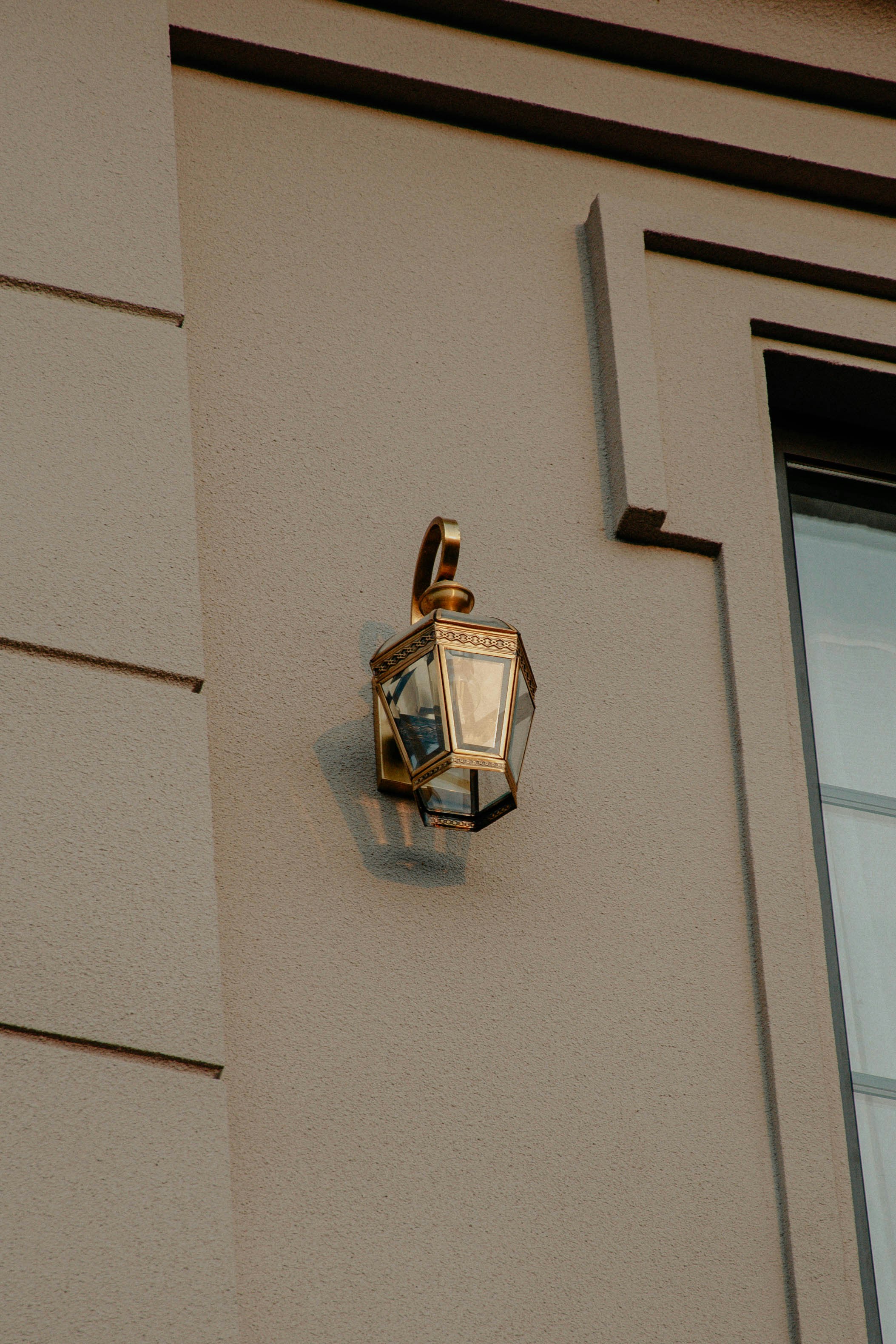 Amber Lantern Adorning a Quiet Facade Under Warm Shadows