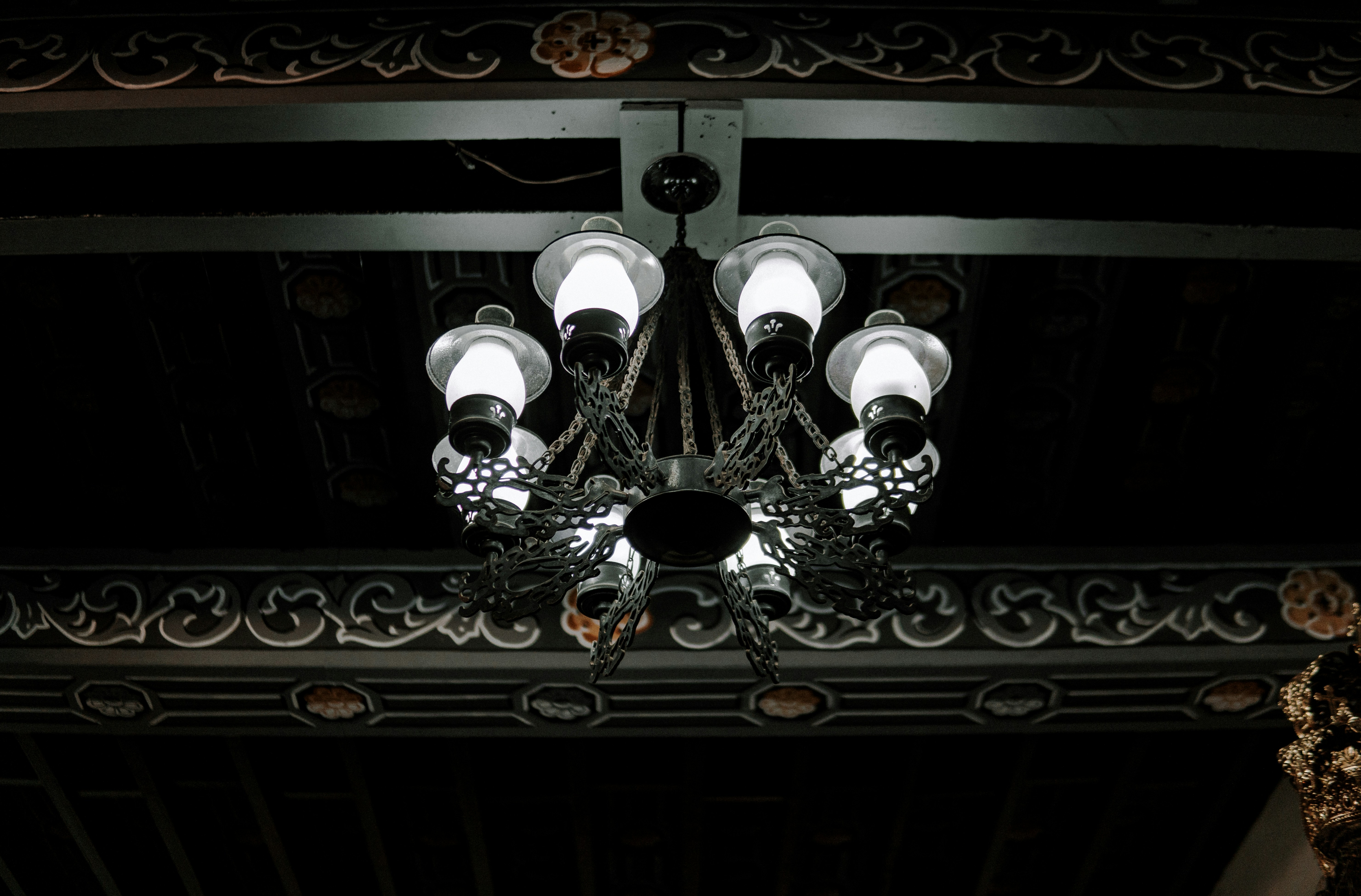 Gilded Glow Beneath a Carved Ceiling: Chandelier in a Dim Hall