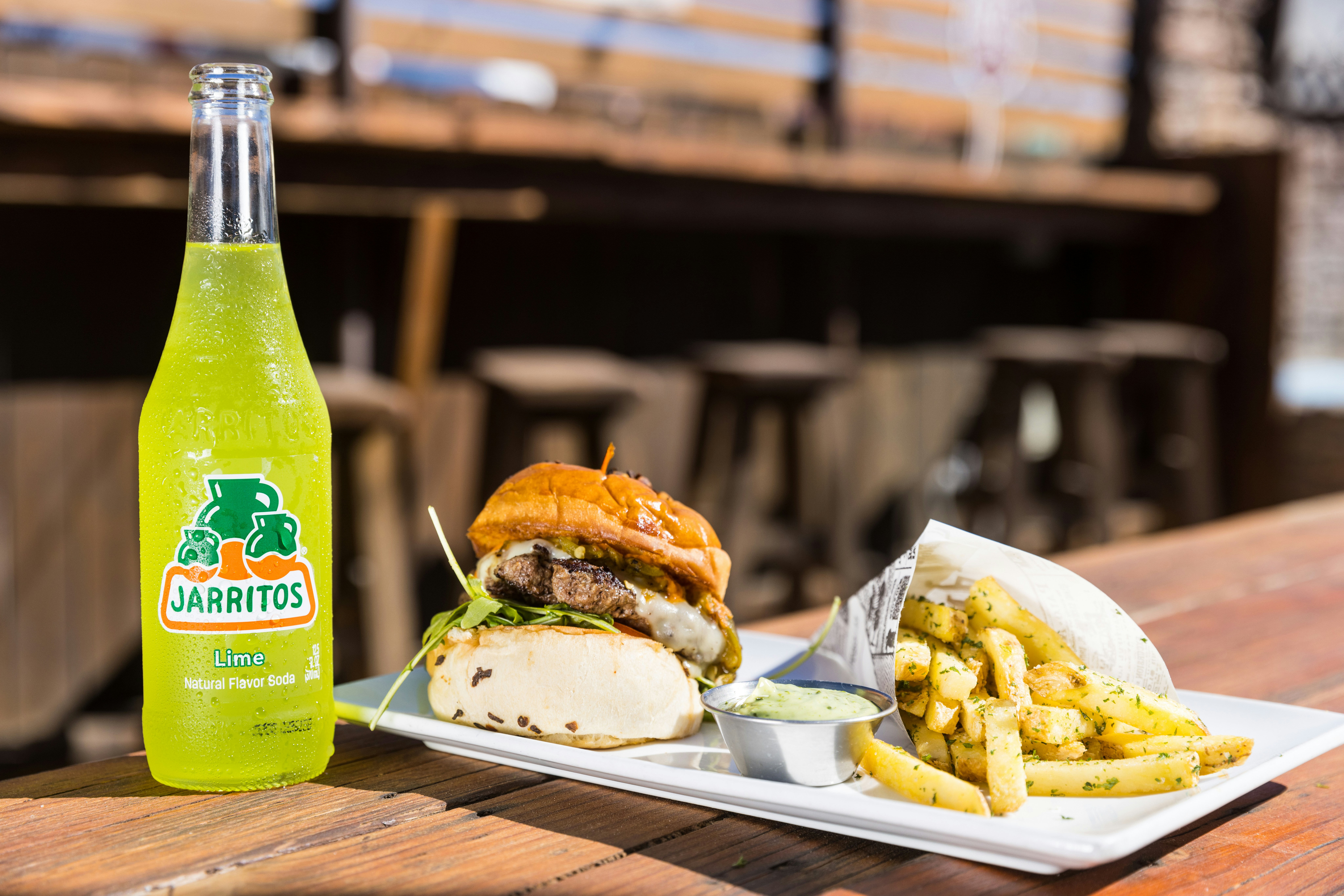 Lime Jarritos and a Gourmet Burger on a Rustic Deck