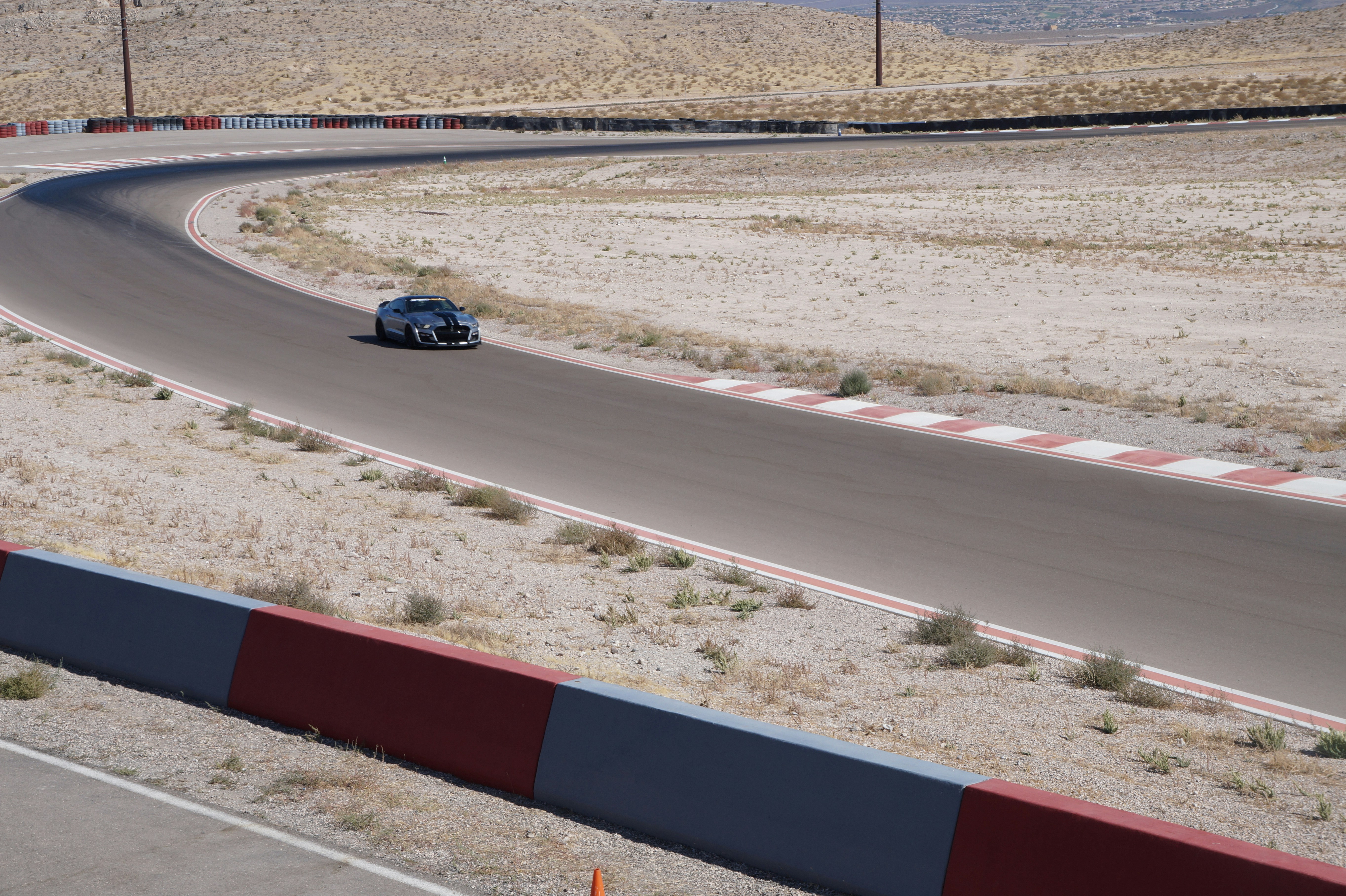 Desert Racetrack: A Lone Car Navigates a Harsh Curve
