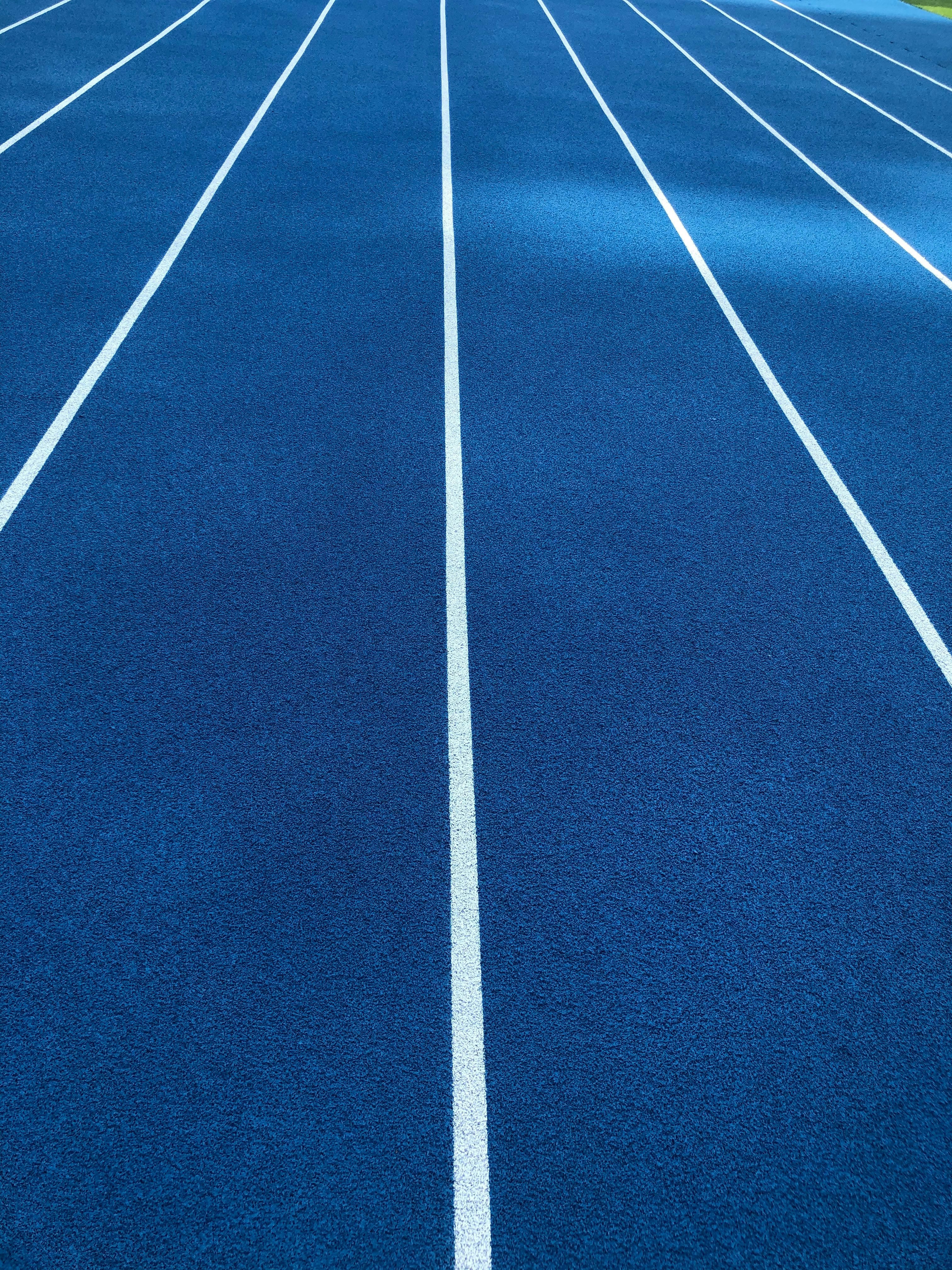 A blue running track with white lines on it photo – Free Racetrack ...