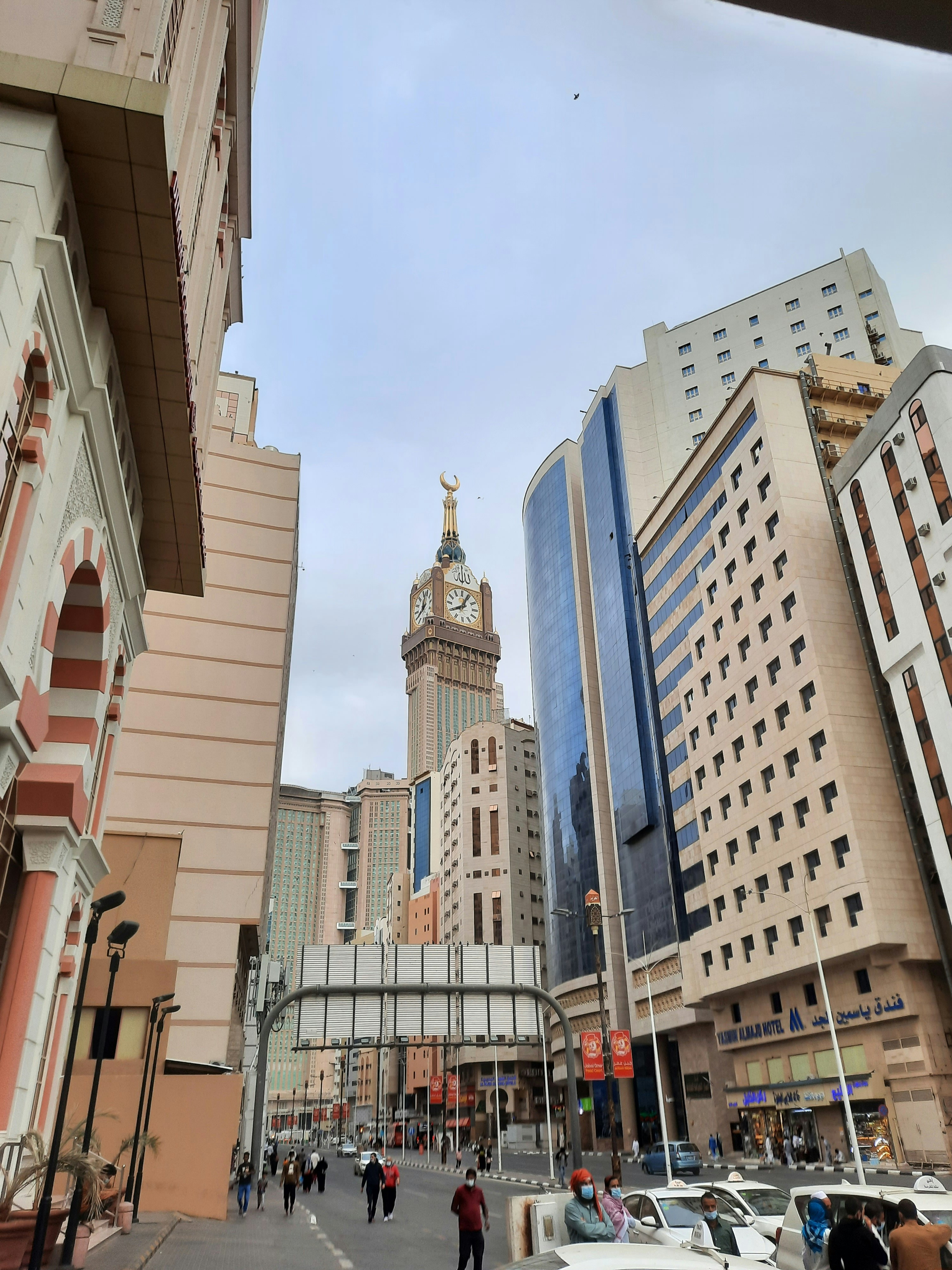 A bustling cityscape with towering skyscrapers framing a prominent clock tower, showcasing a blend of architectural styles and urban life.