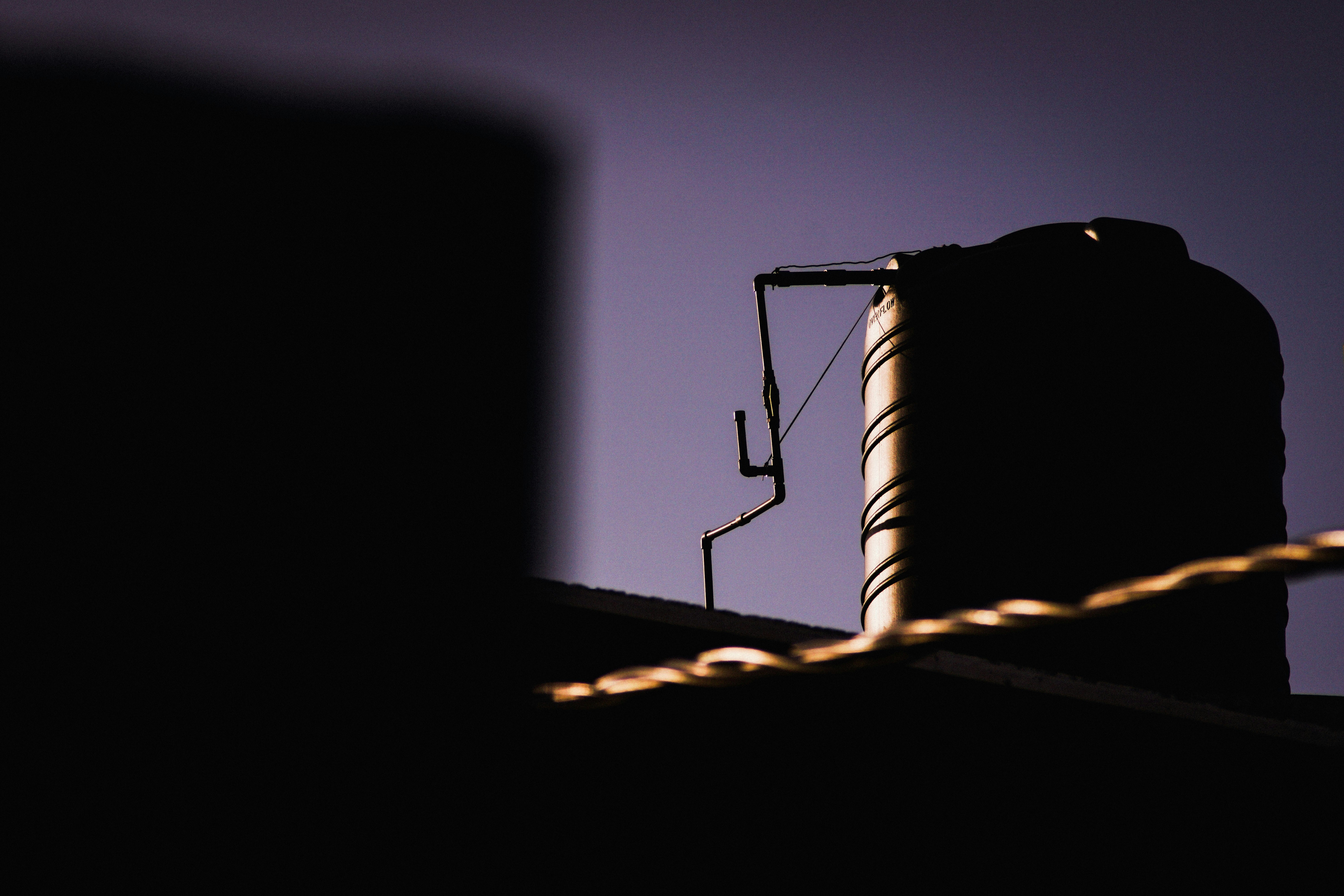 Rooftop Silhouette: Industrial Tank Against Evening Violet