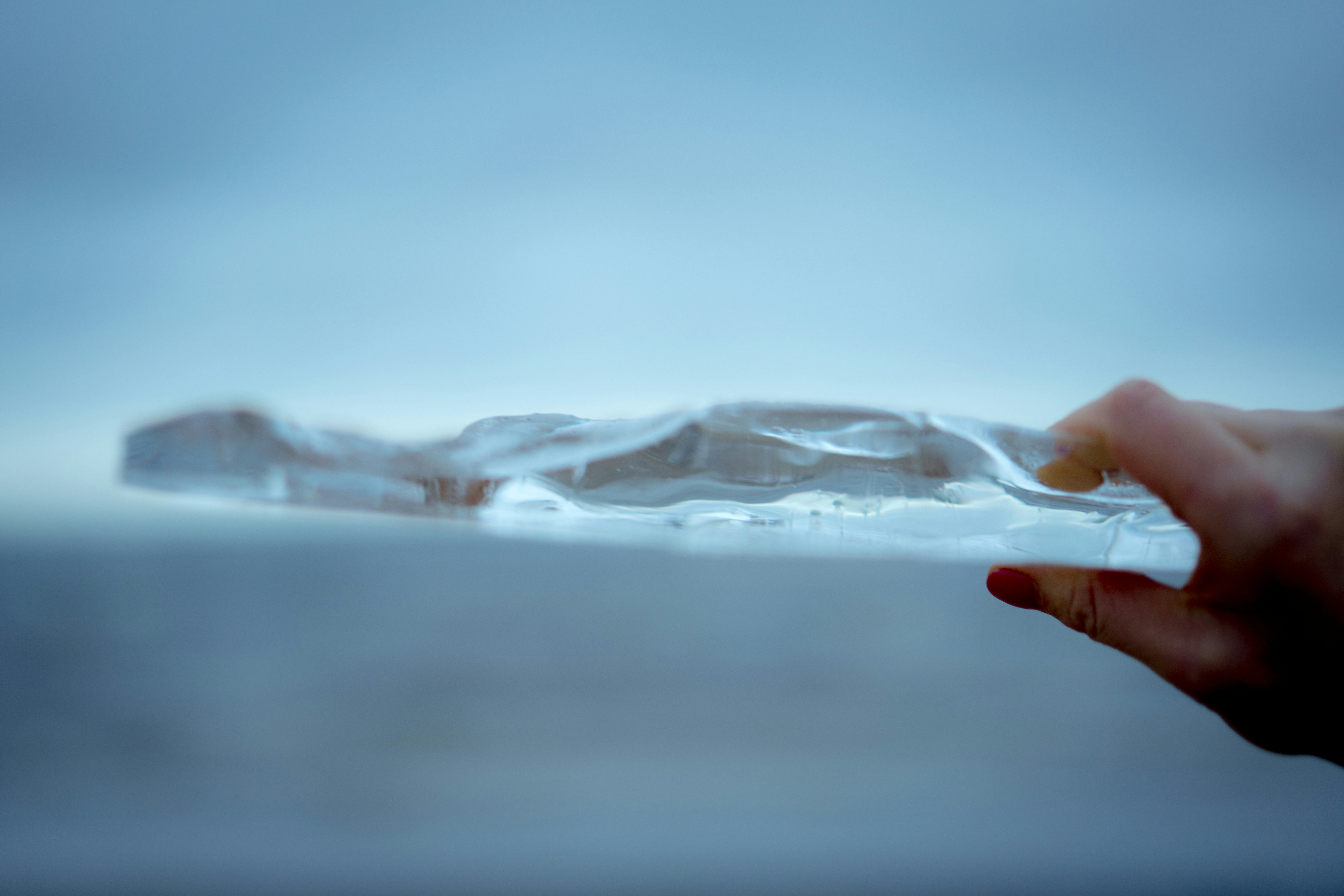 Ice Bar at the Edge: A Hand Reaches for a Frozen Slice Against a Soft Horizon