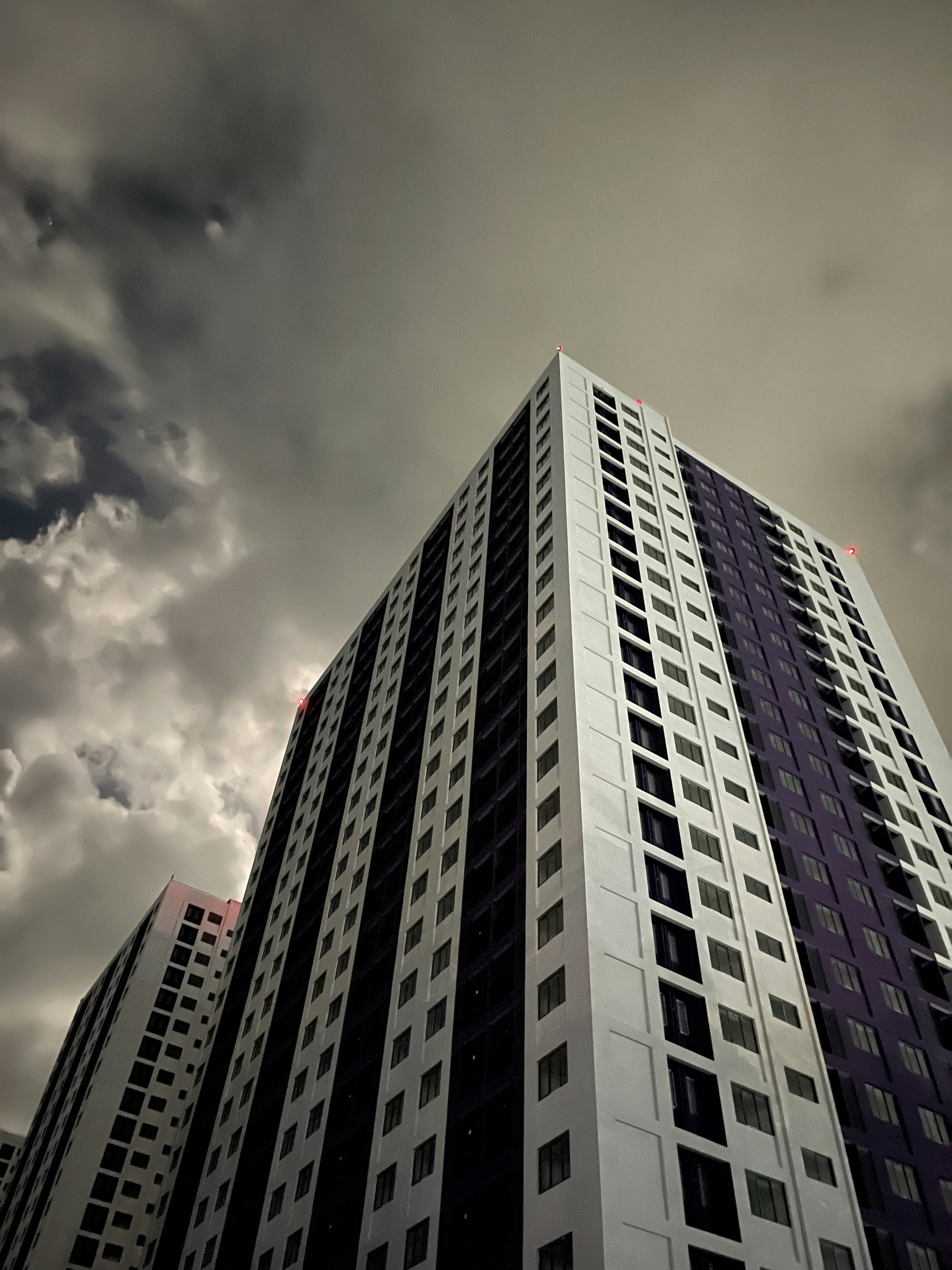 Tall residential buildings rise dramatically against a moody sky, accentuated by the interplay of light and shadow.