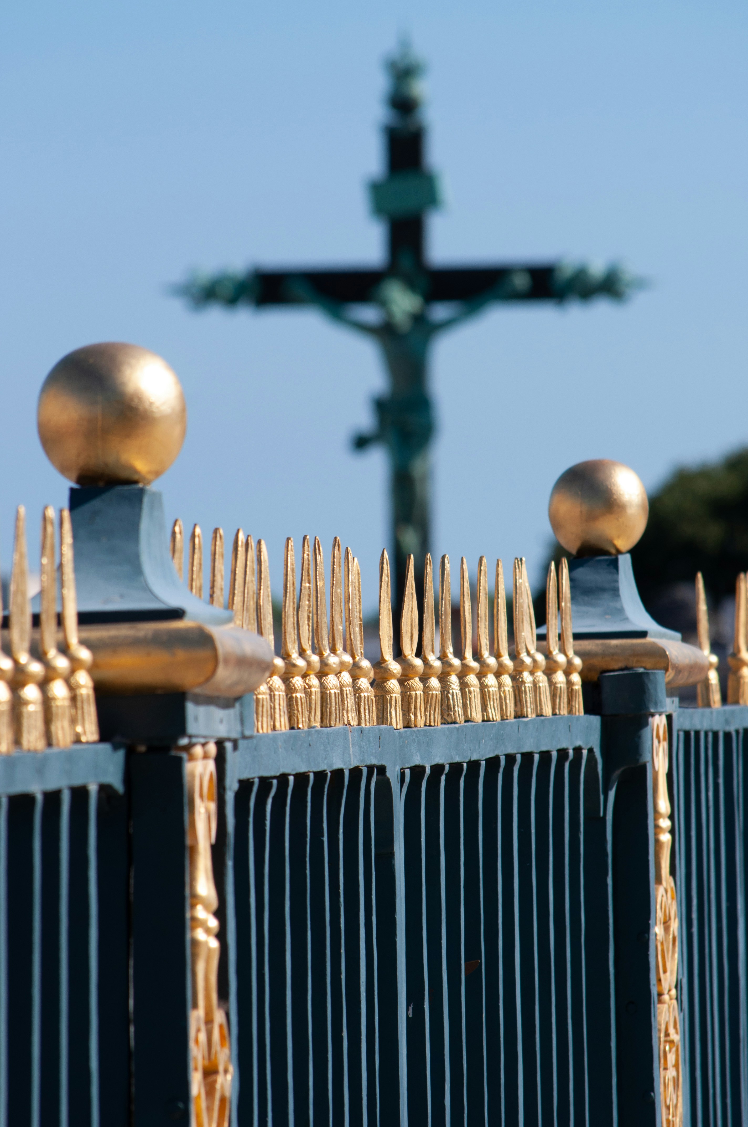 Gilded Orbs Guard a Blue Fence Toward a Distant Cross
