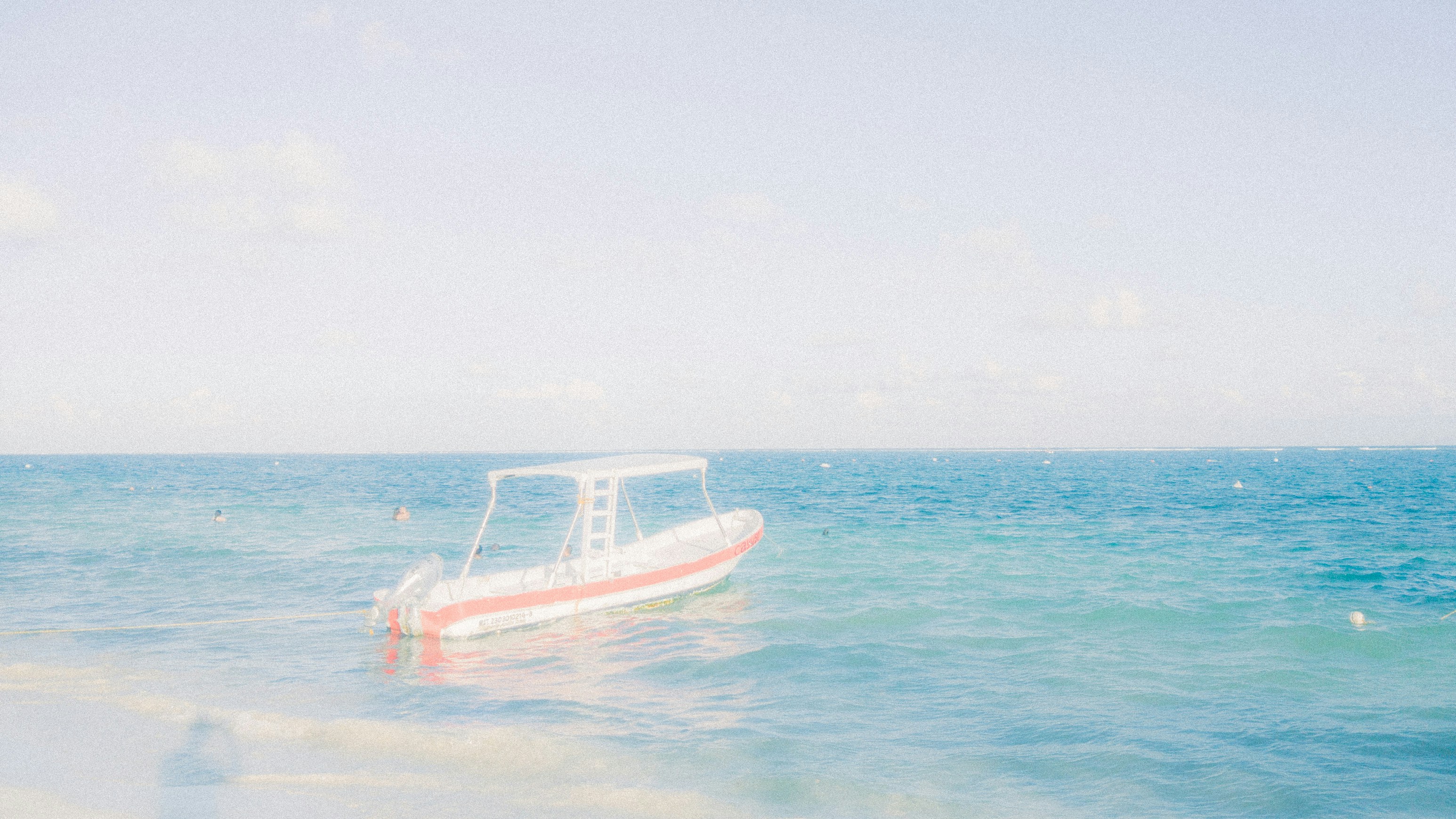 A vibrant boat gently floats on calm turquoise waters, with a soft, dreamy atmosphere enveloping the scene.