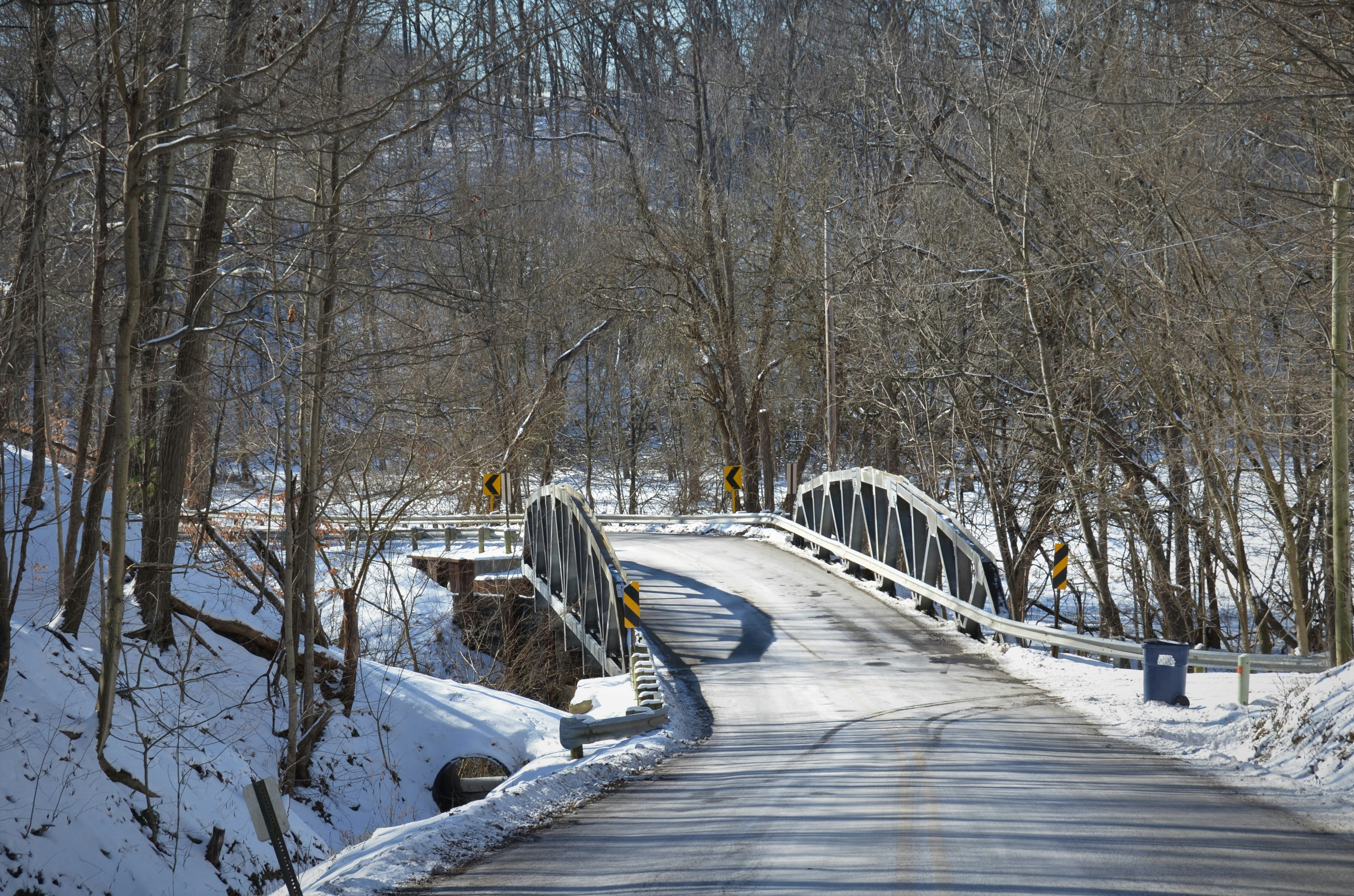 A snow covered road with a bridge in the background photo – Free ...
