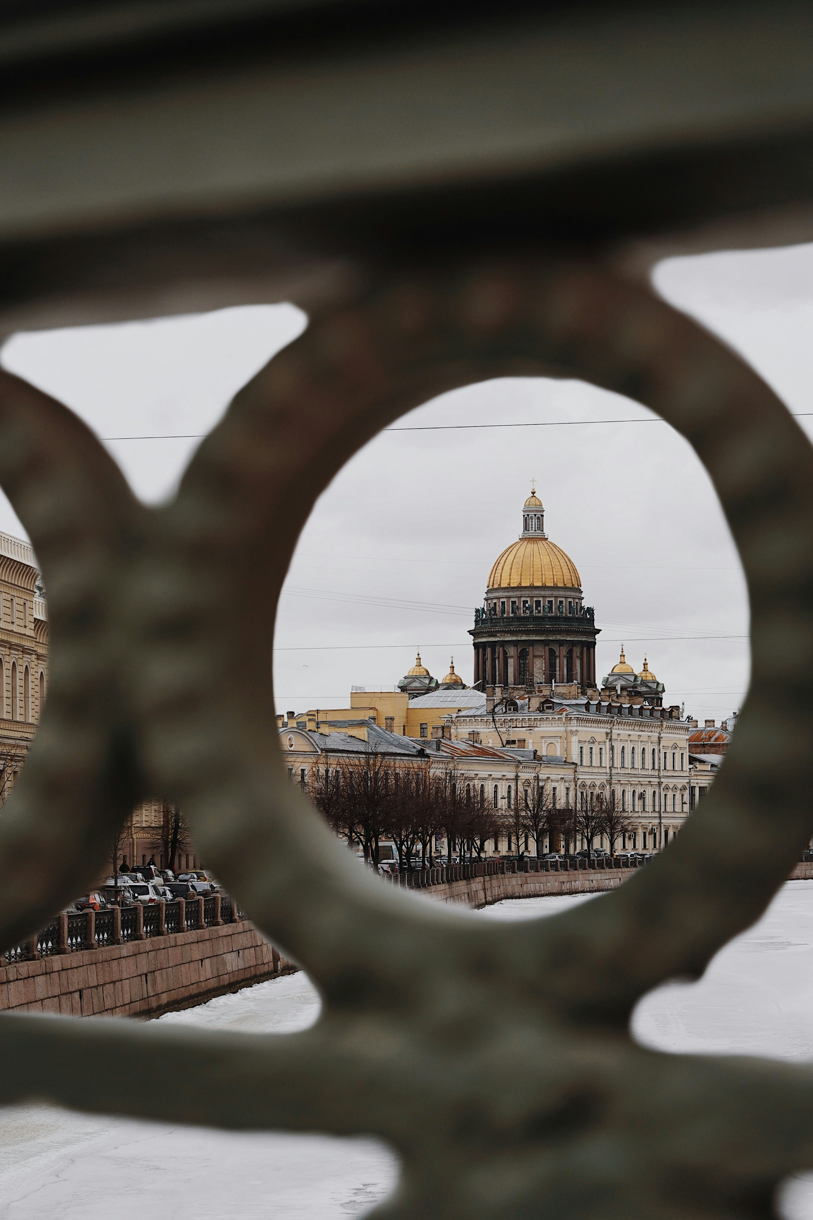 Through Circular Ironwork: A Gold-Domed Cityscape Framed in Winter
