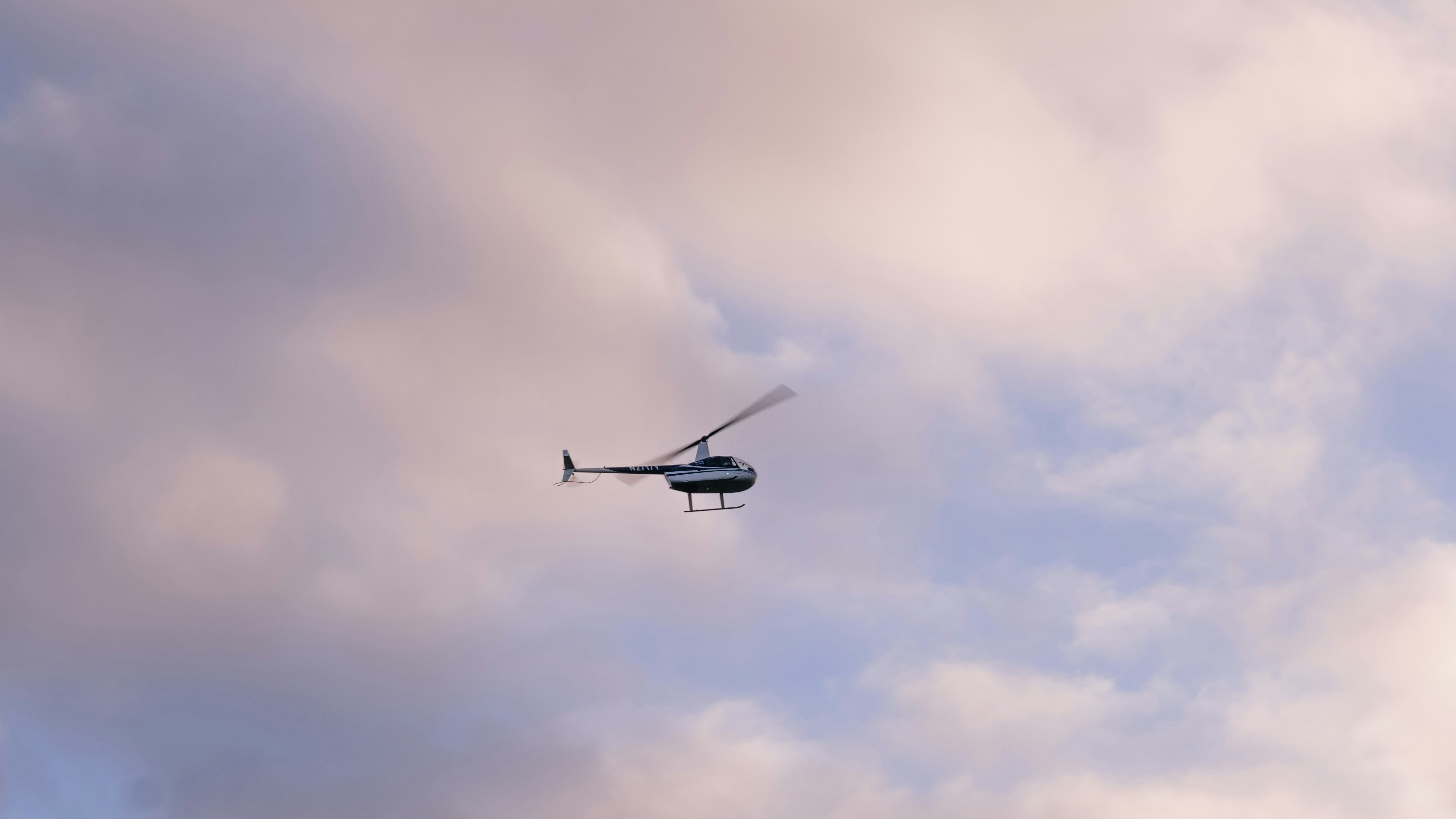 Foto Un helicóptero volando a través de un cielo azul nublado – Imagen ...