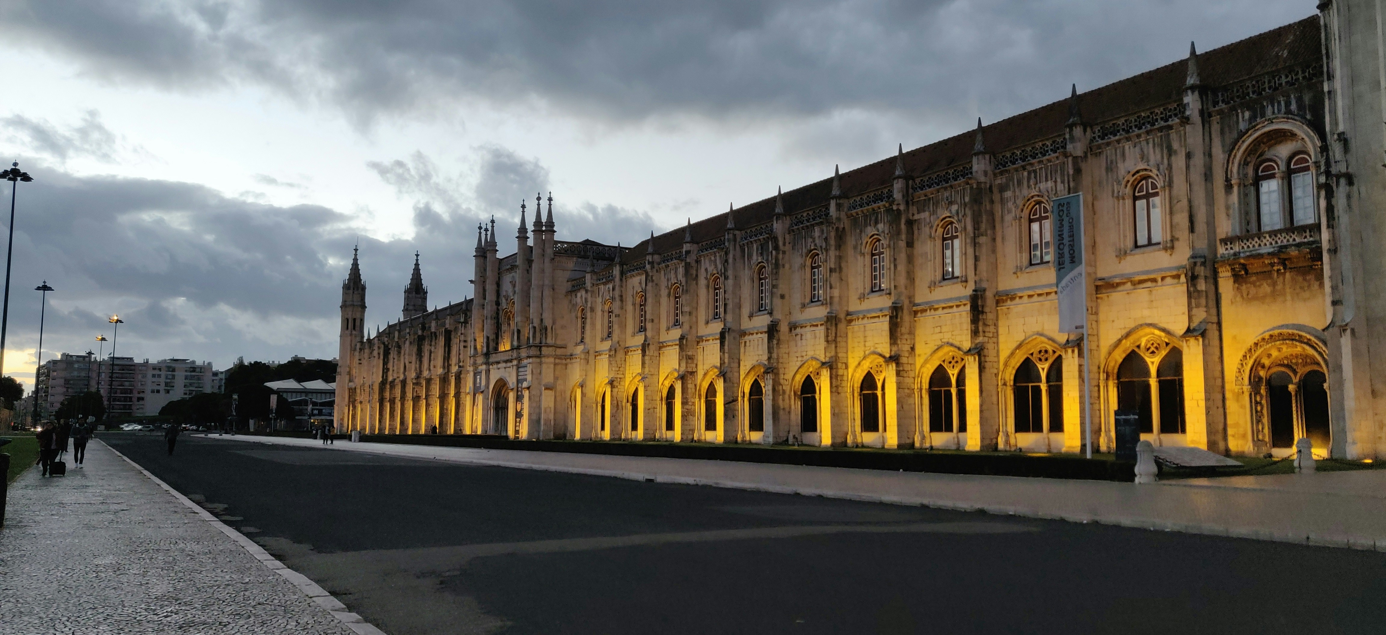 Illuminated historic building with arched windows under a cloudy evening sky.