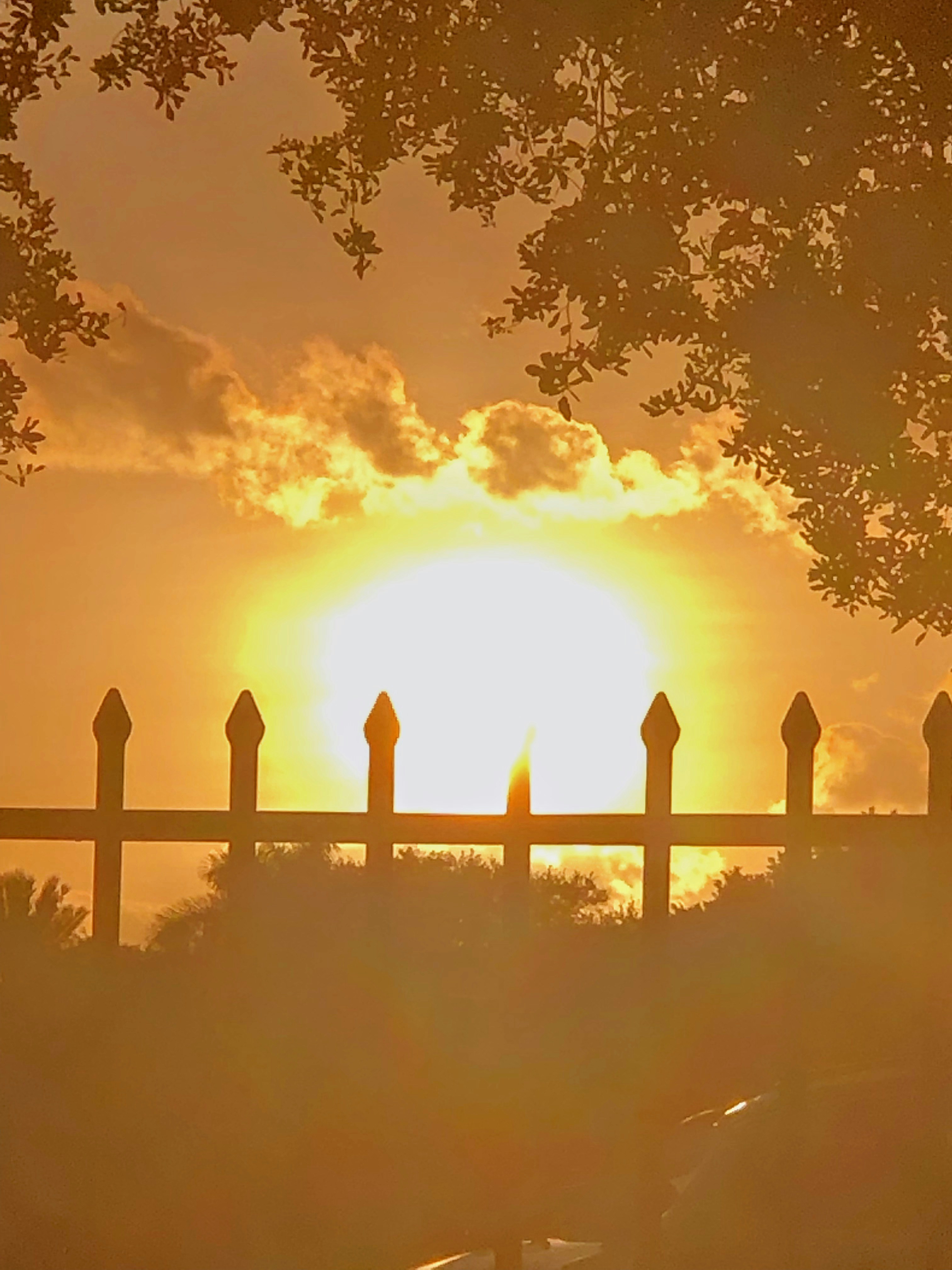 the sun is setting behind a wooden fence