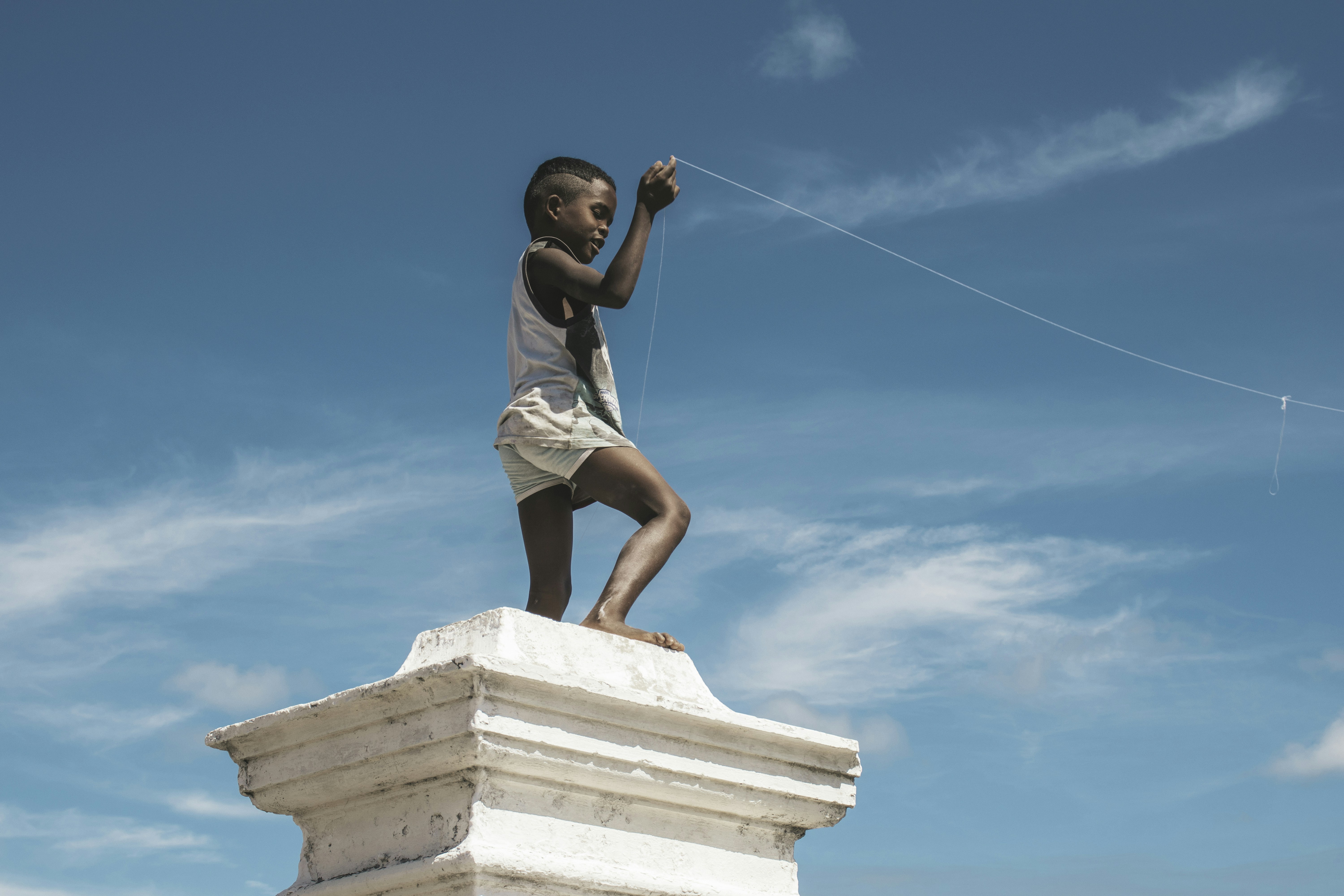 A young boy flying a kite on top of a statue photo – Free Person Image ...