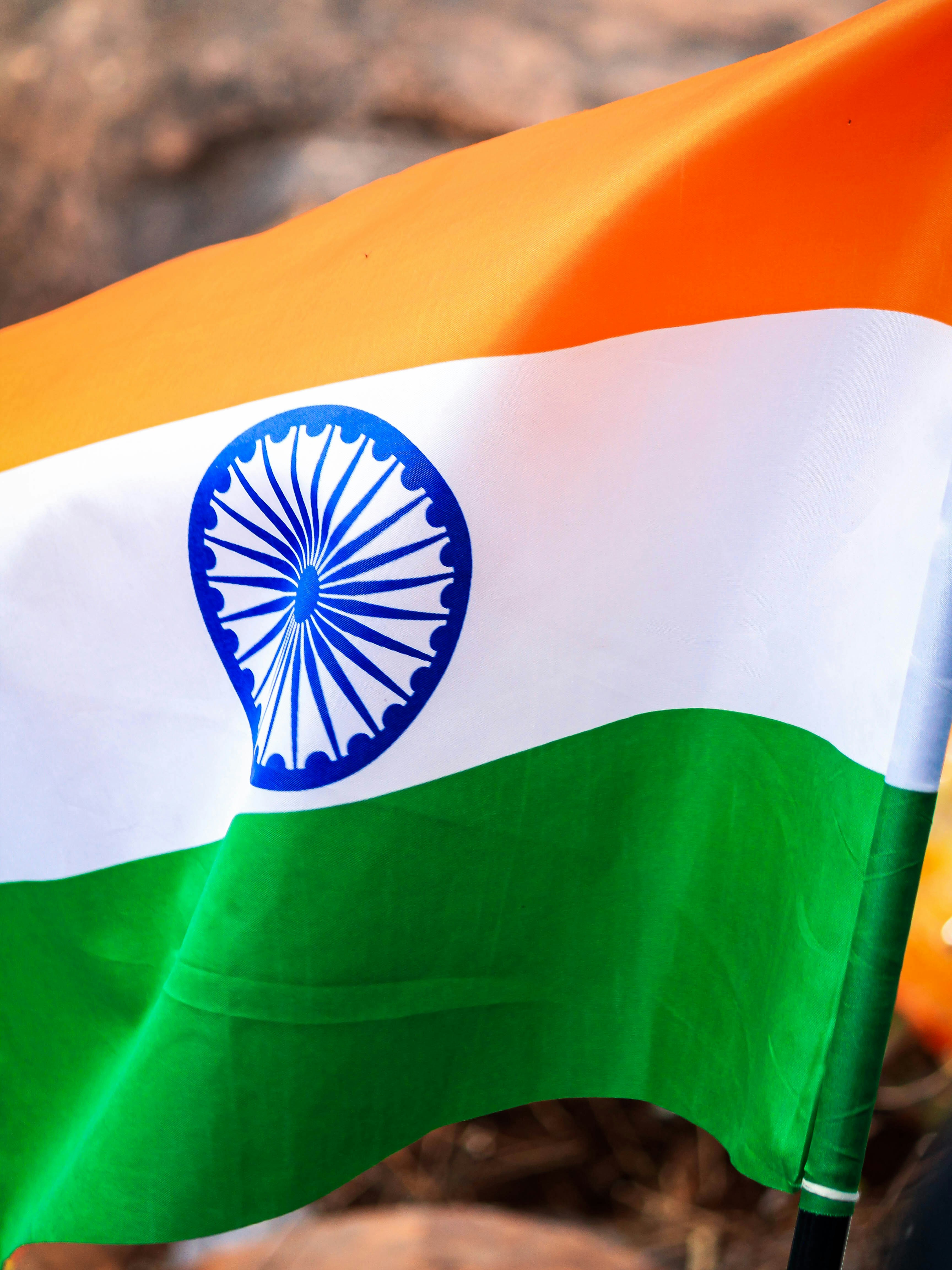 Vibrant Indian national flag fluttering against a blurred natural backdrop, showcasing its distinct colors and emblem.
