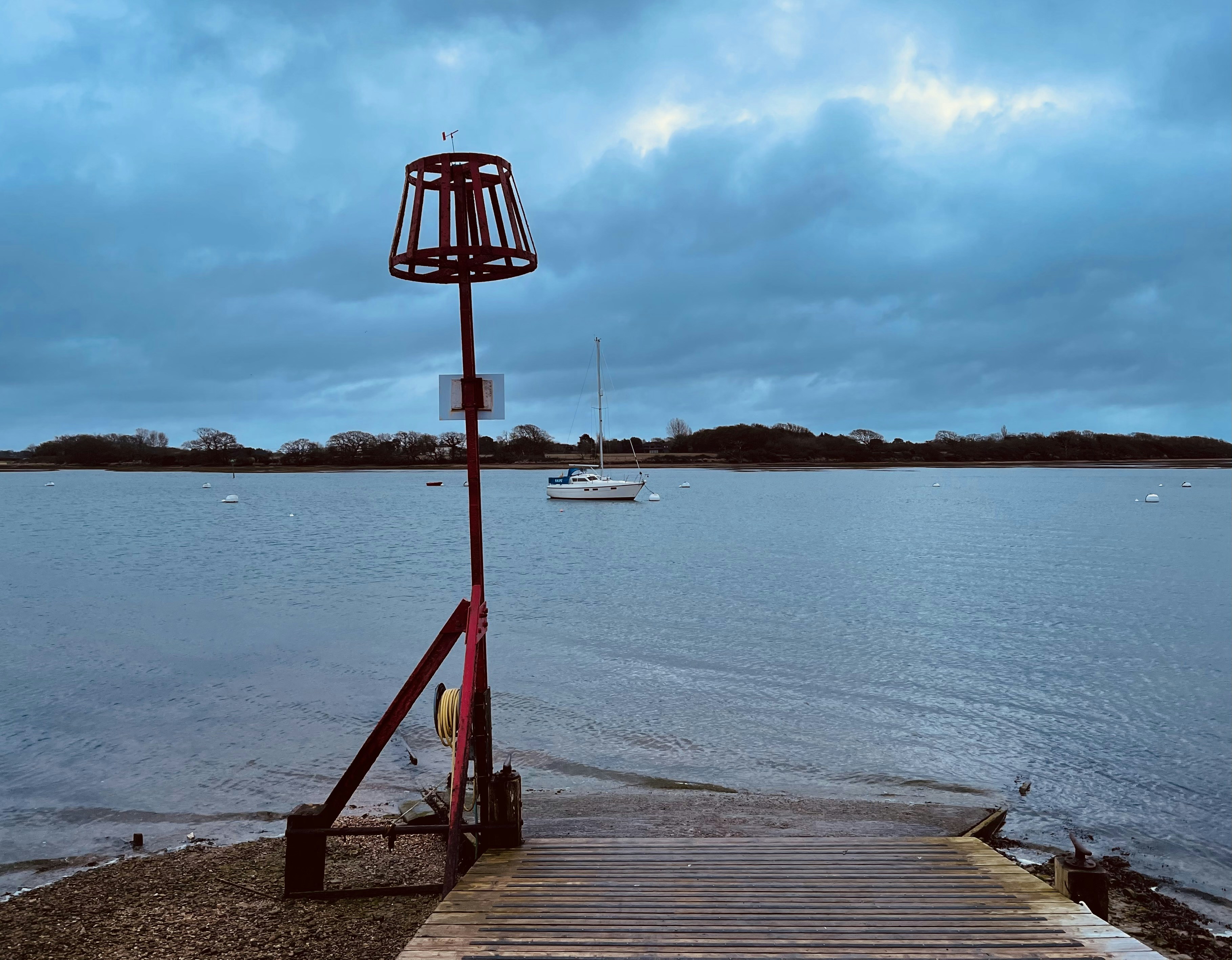 Red Dock Marker Framing a Quiet Lake with a Distant Sailboat