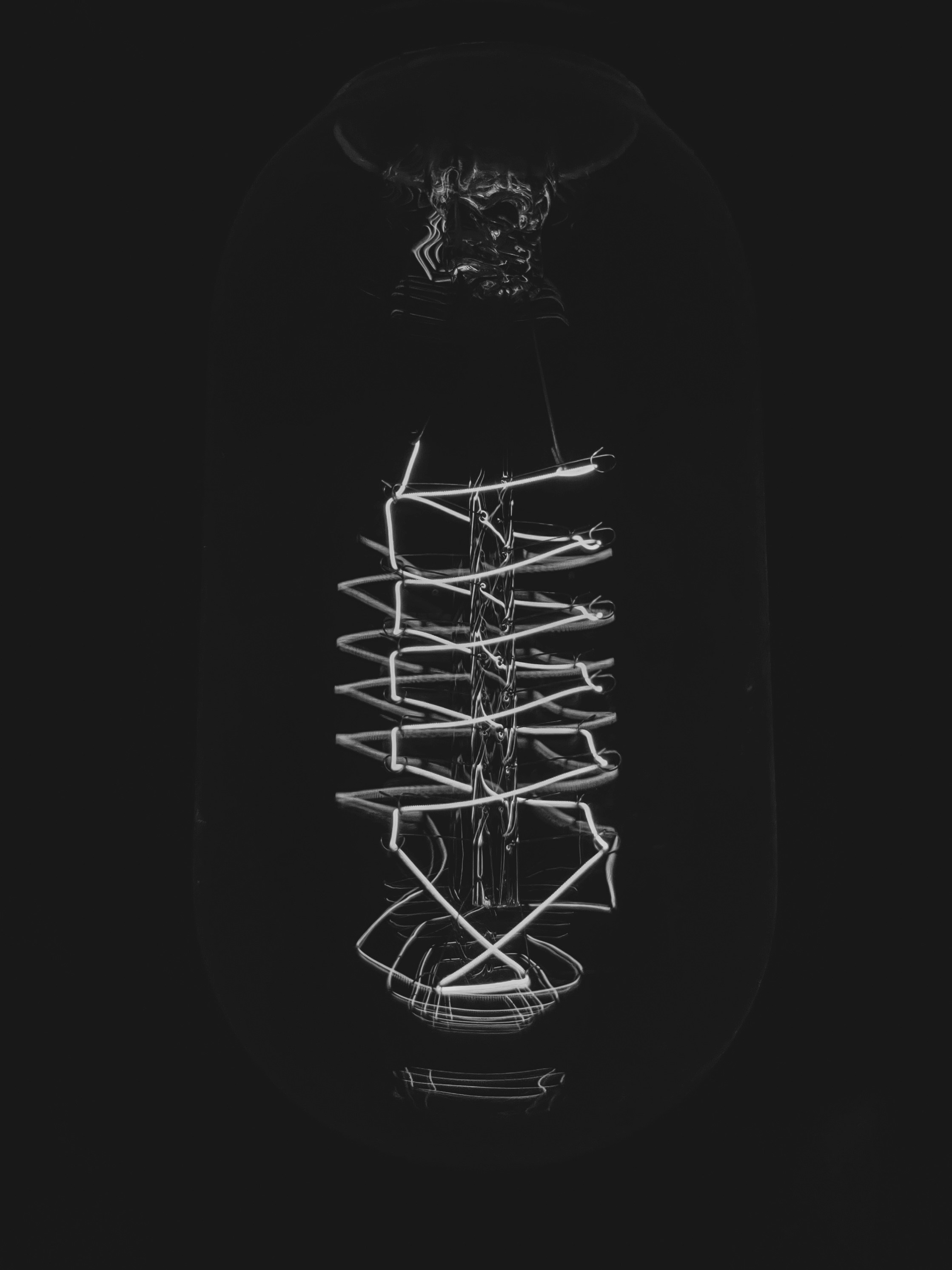 Intricate vintage light bulb filament glowing against a dark backdrop, showcasing its unique spiral design.