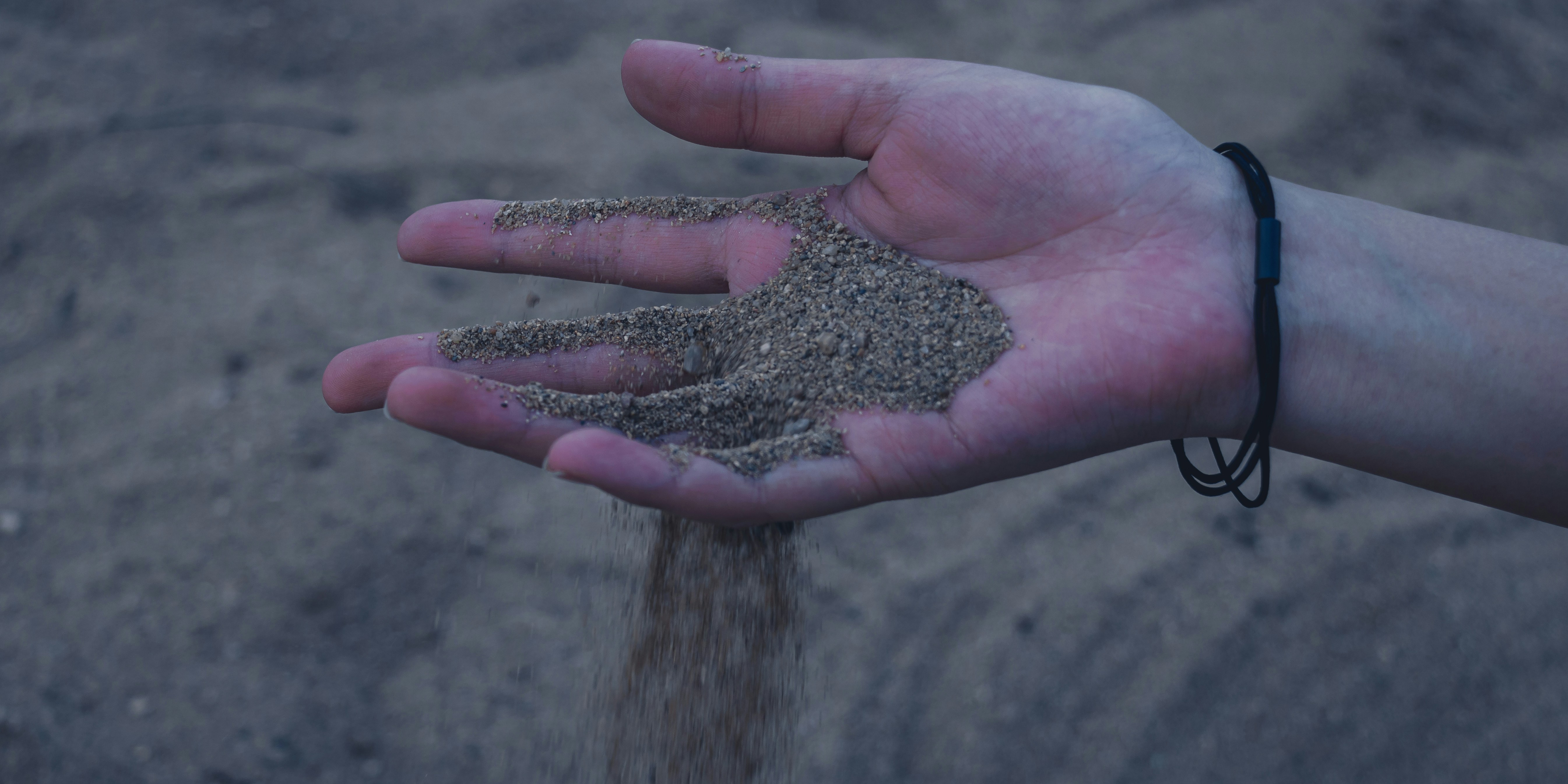 A person holding sand in their hand on the beach photo – Free Person ...