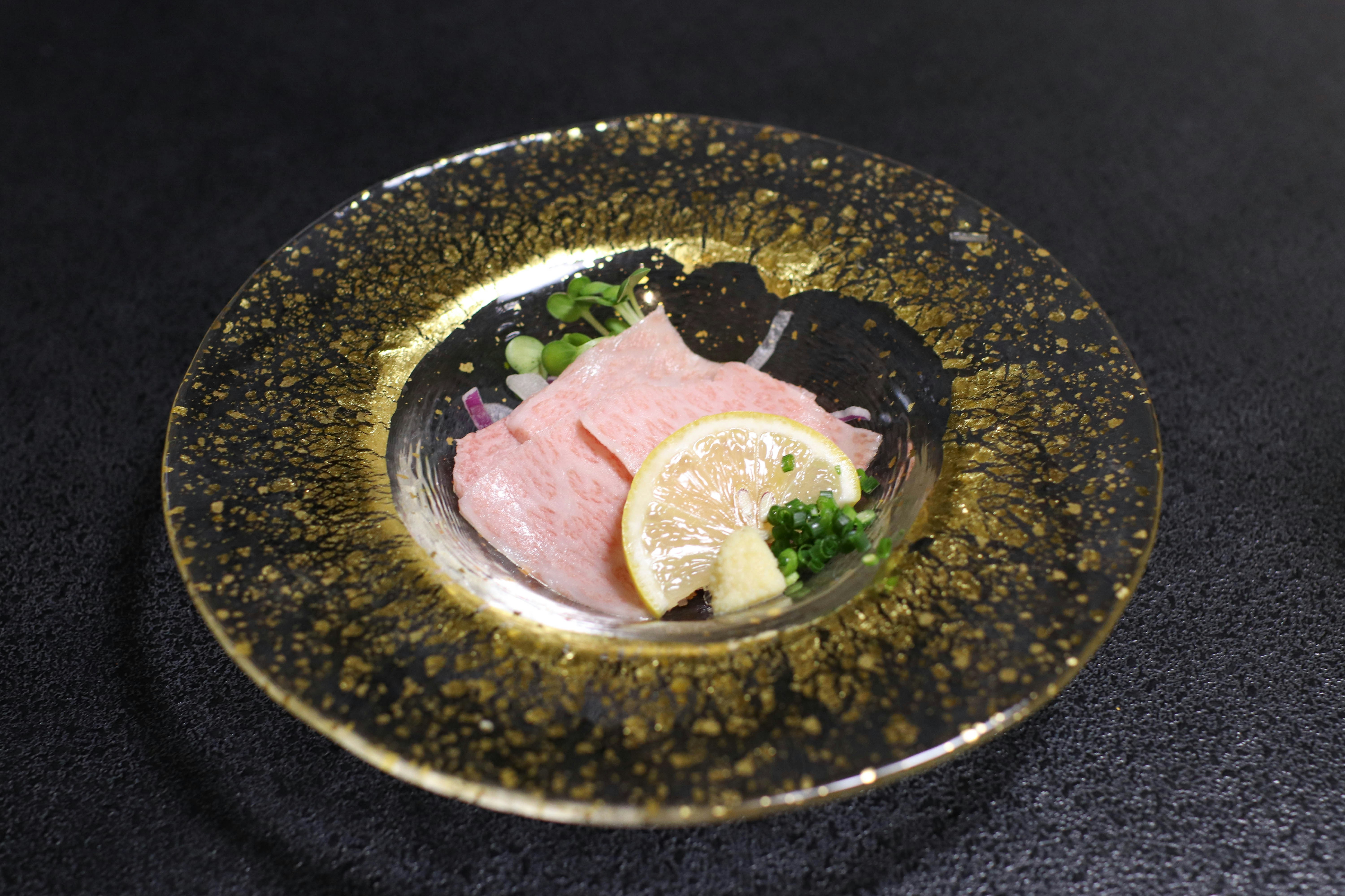 Gold-speckled lacquer plate frames a citrus-kissed sashimi centerpiece