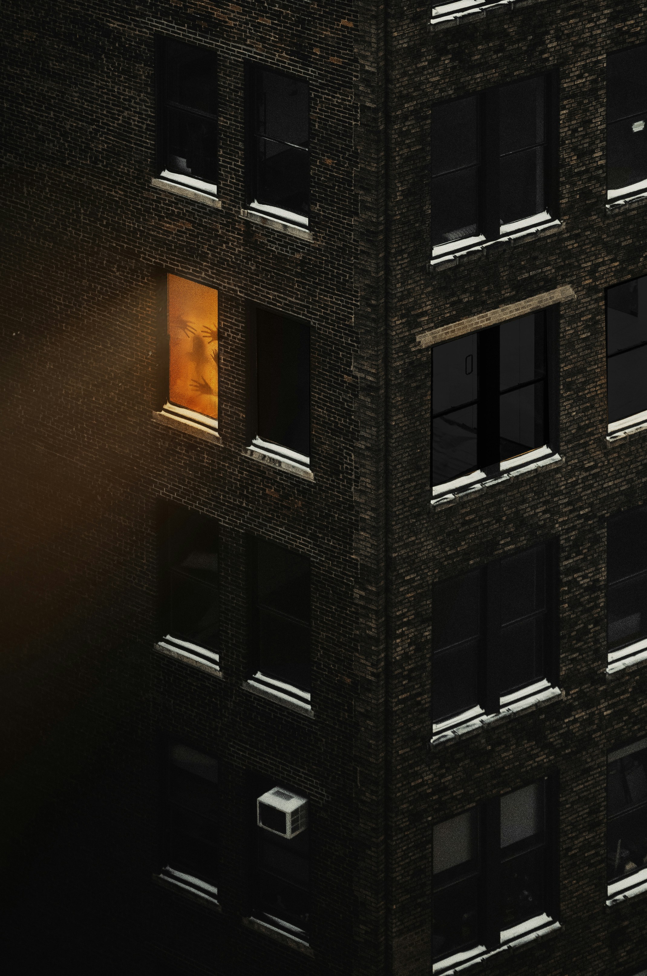 Orange Beacon Behind Brick Facade: Night Window in an Urban Brick Block
