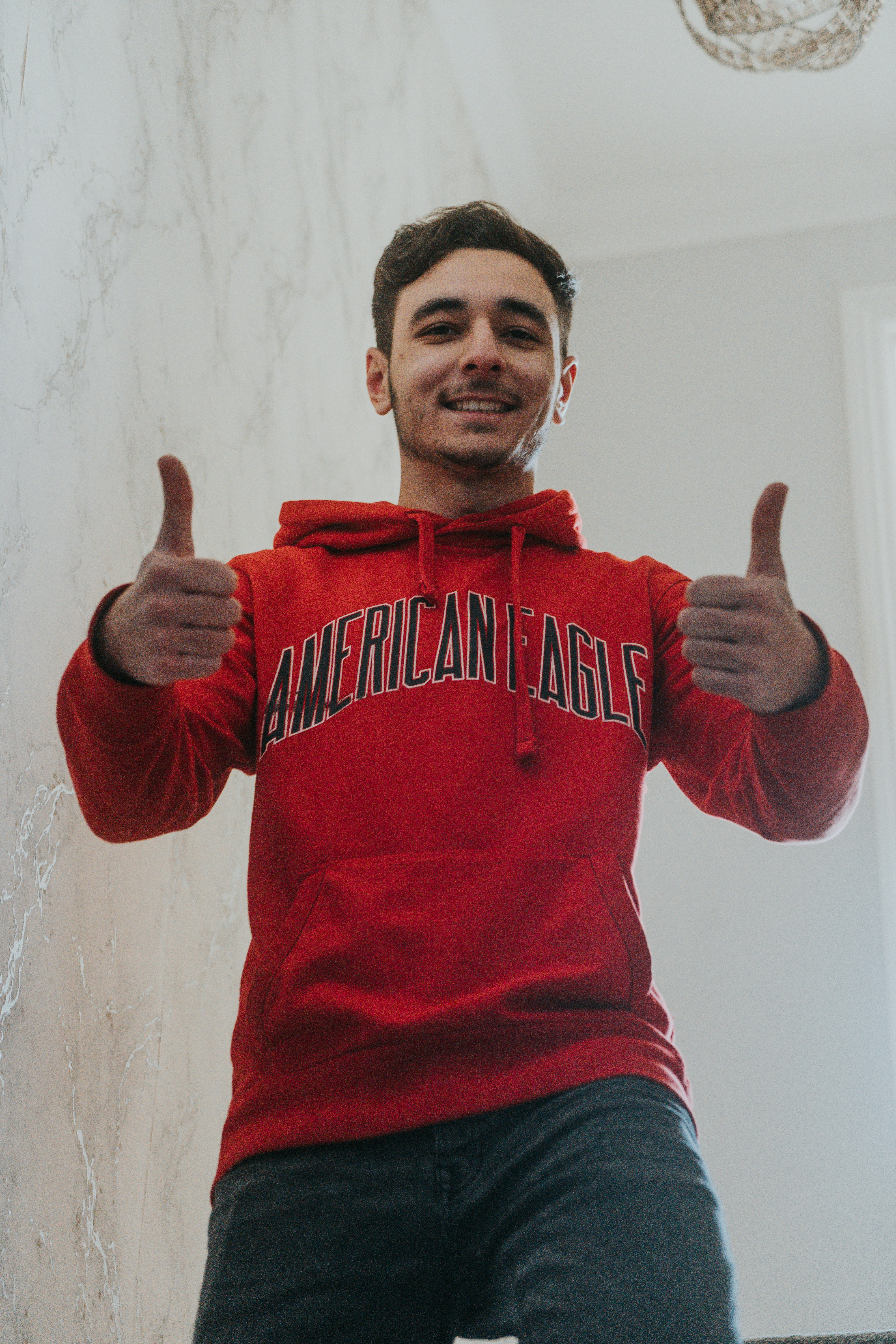 Low-Angle Cheer: A Red-Hoodie Moment in a Bright Hall