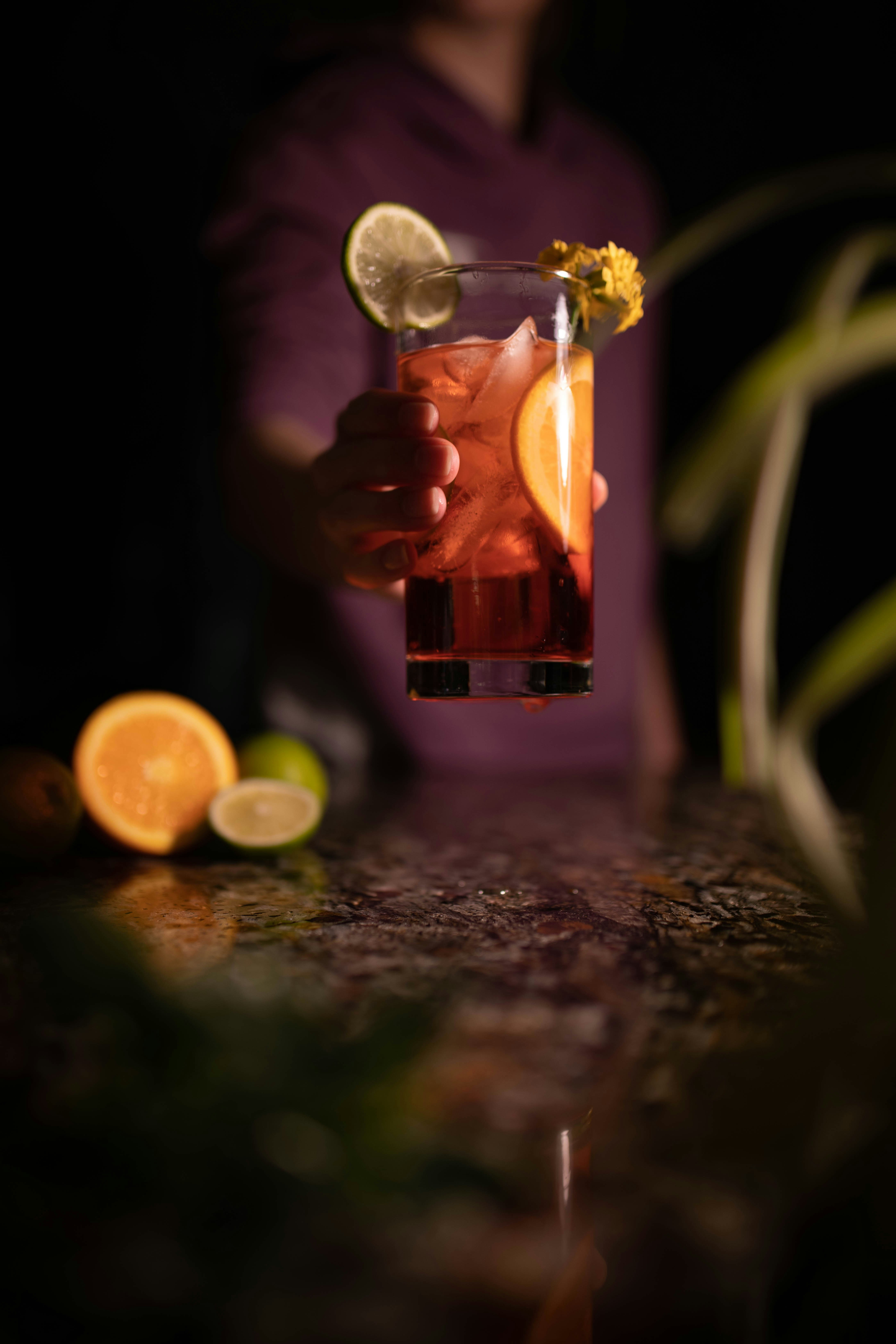 Midnight Citrus Pour: A Pink Cocktail Shared Across a Shadowed Bar