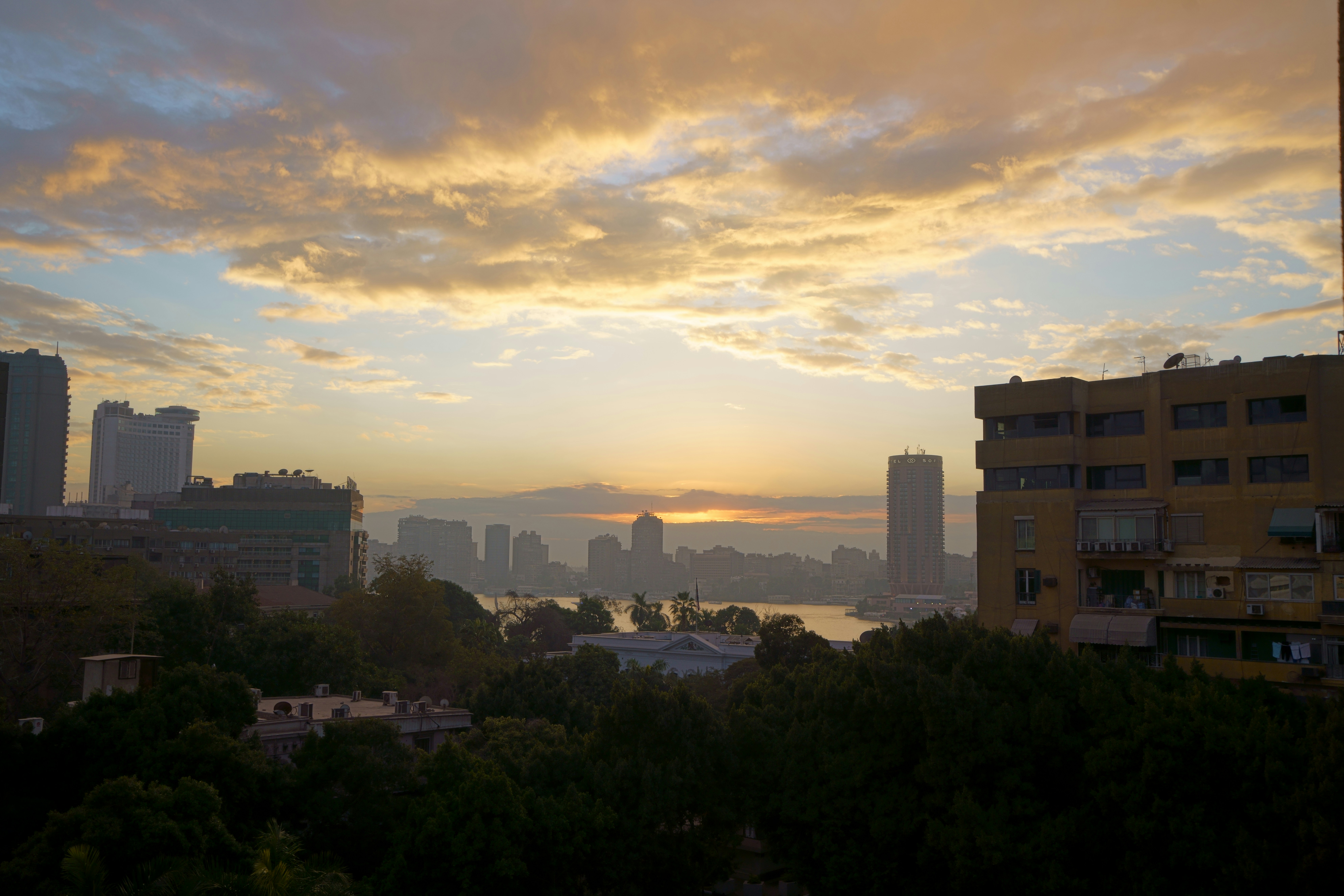 The sun is setting over a city with tall buildings photo – Free Cairo ...