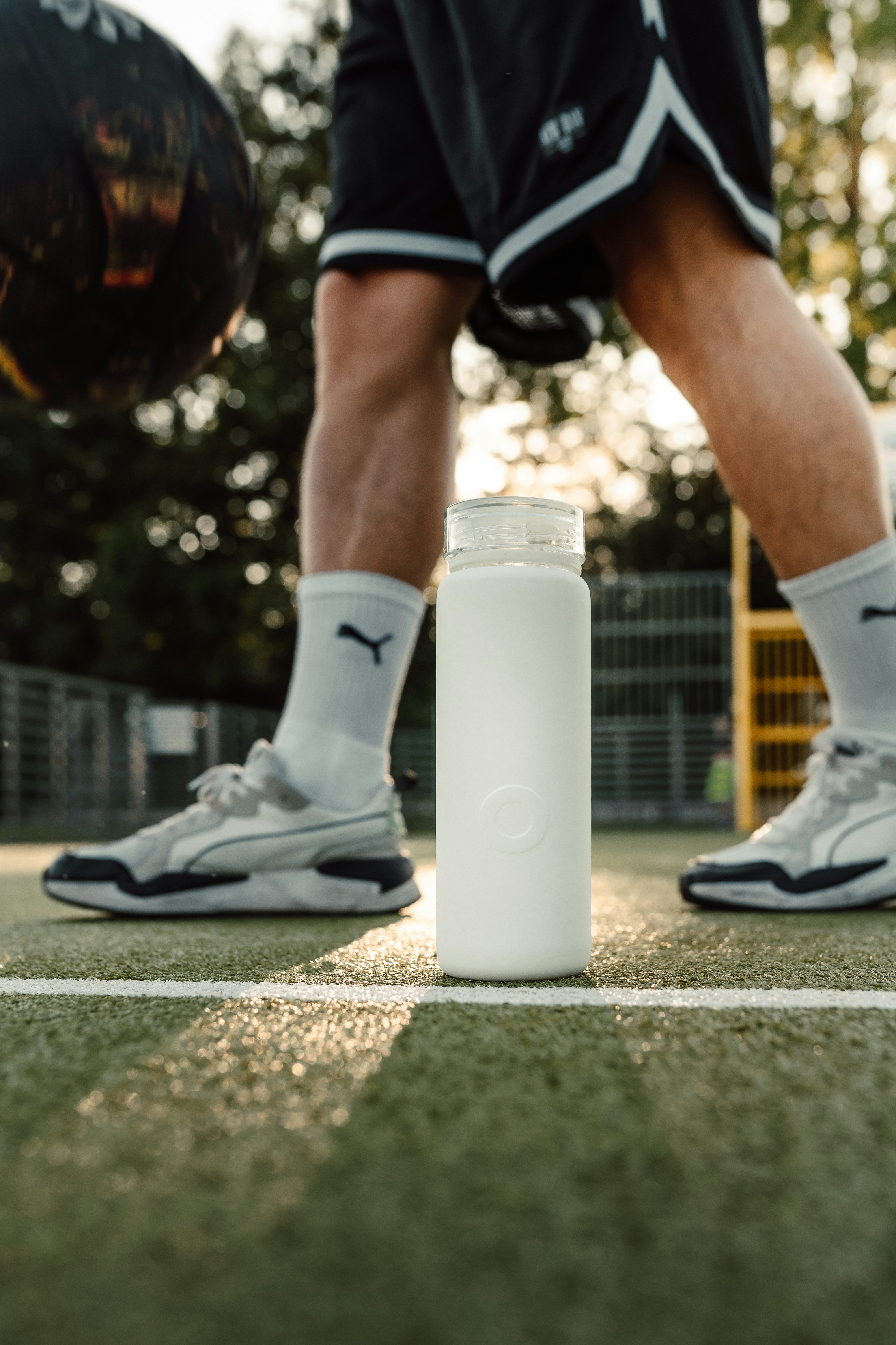 Hydration Stand: A Ground-Level Shot of a White Bottle Between Athletic Feet