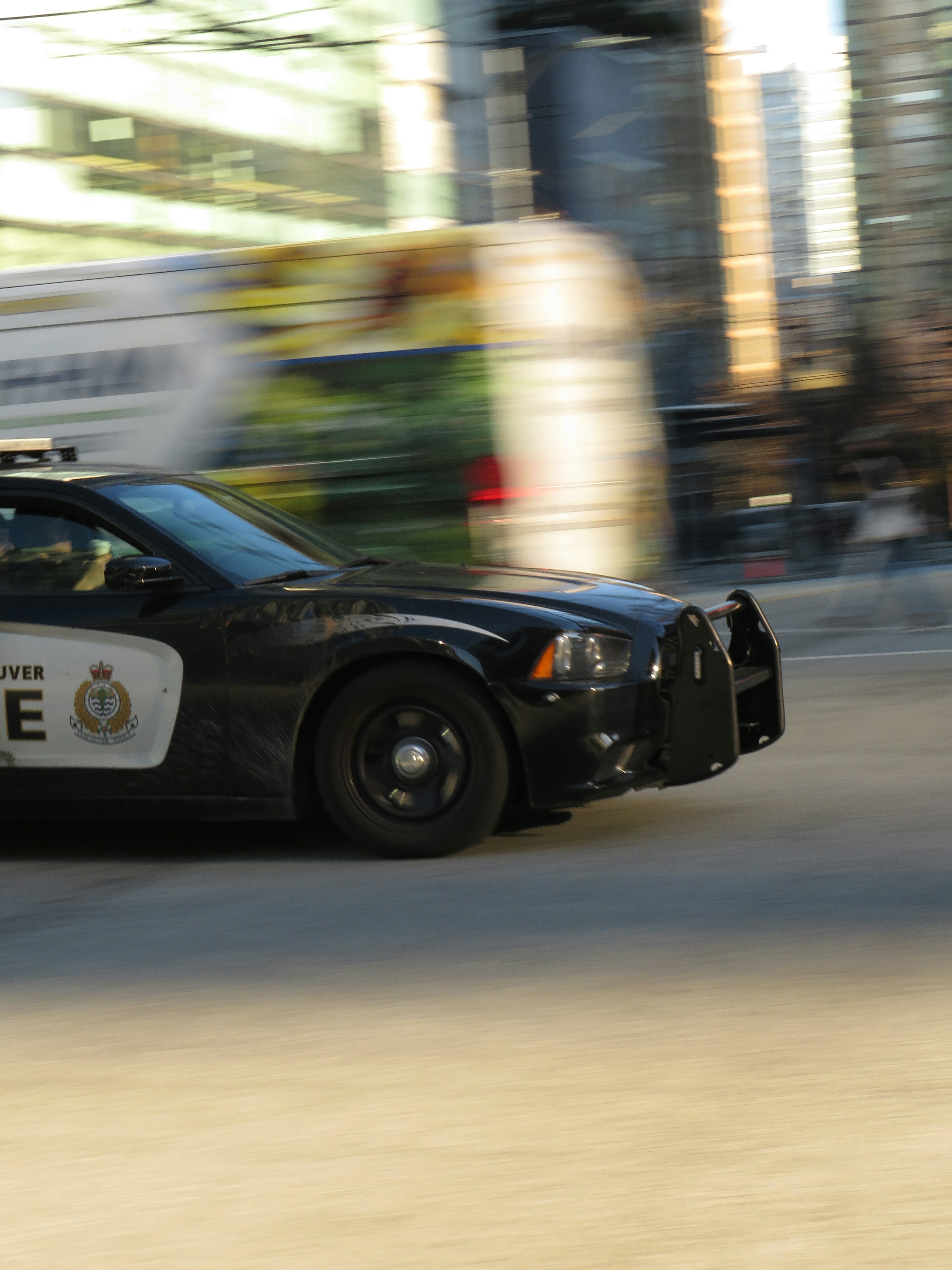 A police car driving down a city street photo – Free Police department ...