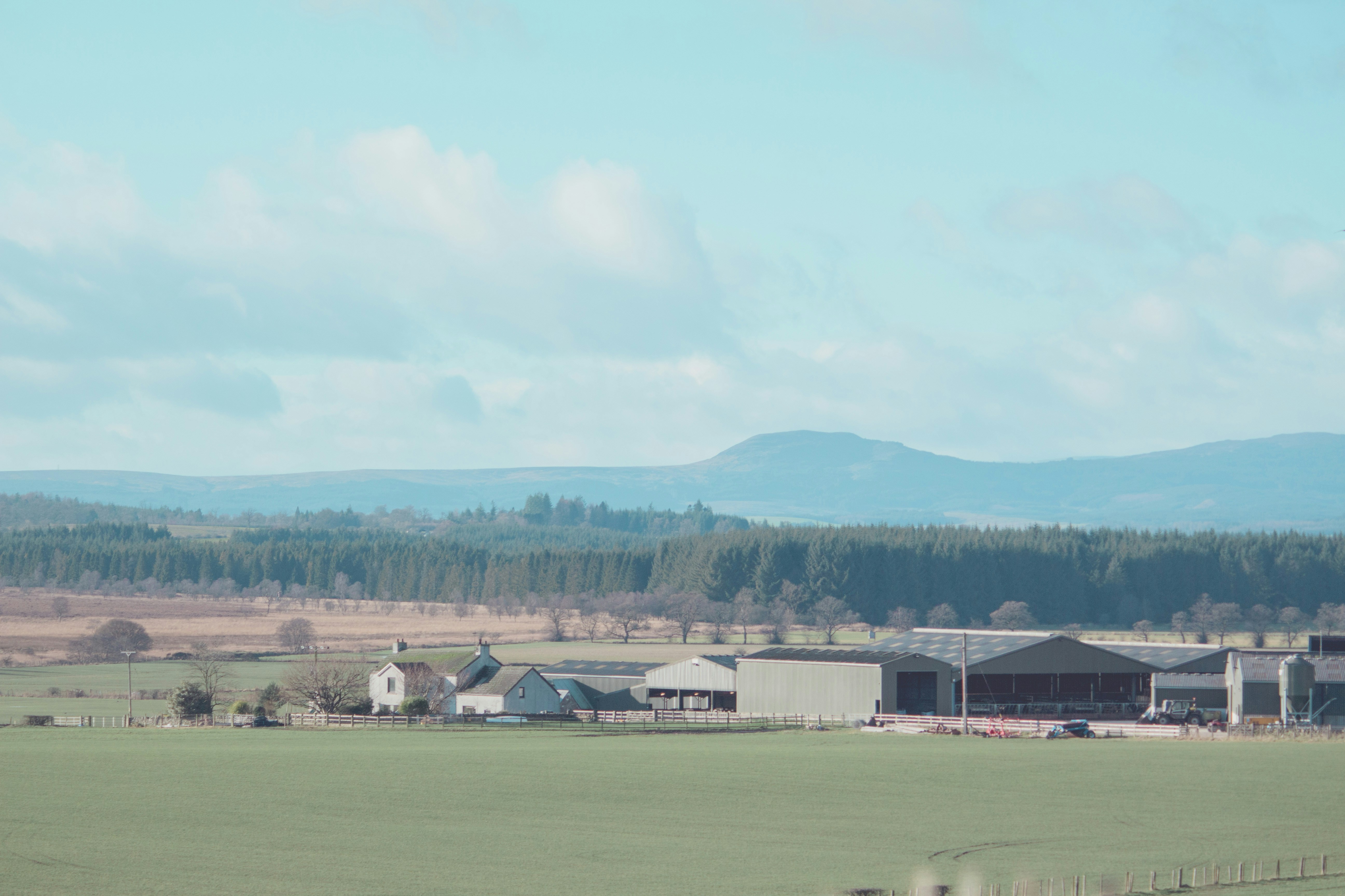Expansive farmland with distant hills under a soft blue sky.