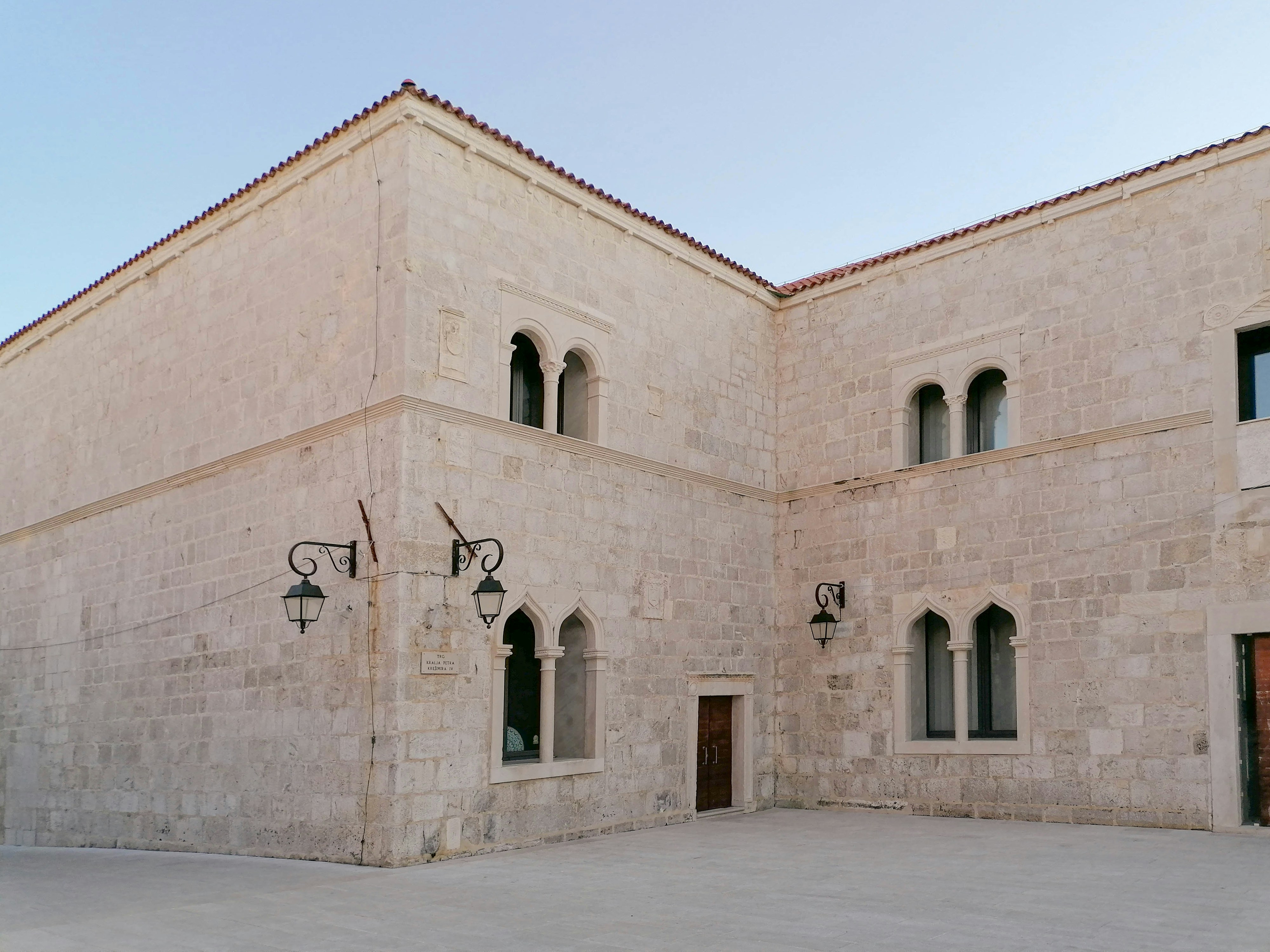 Sunlit Limestone Courtyard: Arched Windows Framing a Stately Door