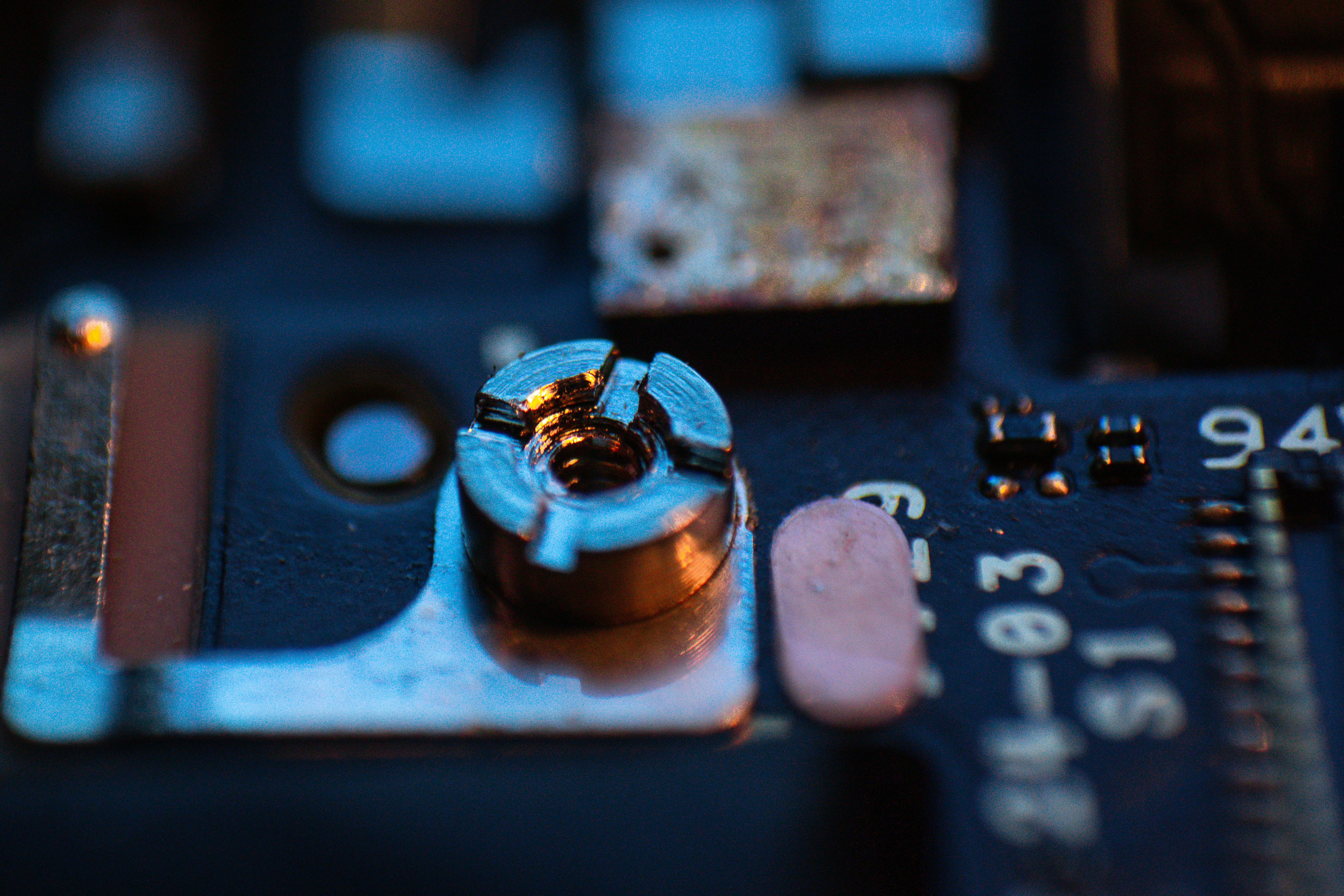 Close-up of a metallic component on a circuit board, showcasing intricate details and textures. The lighting highlights the craftsmanship of electronic design.