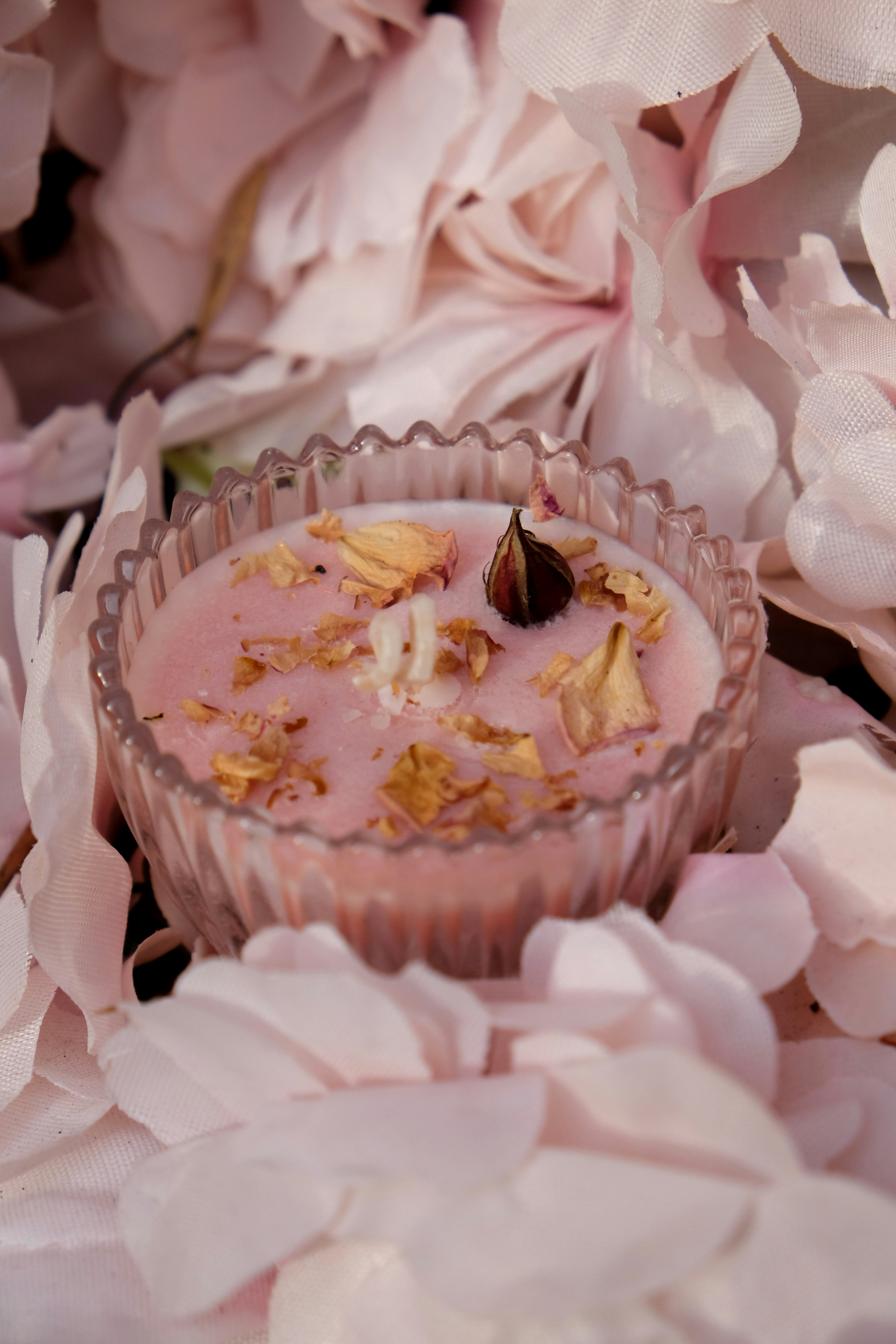 a cupcake sitting on top of a table surrounded by pink flowers